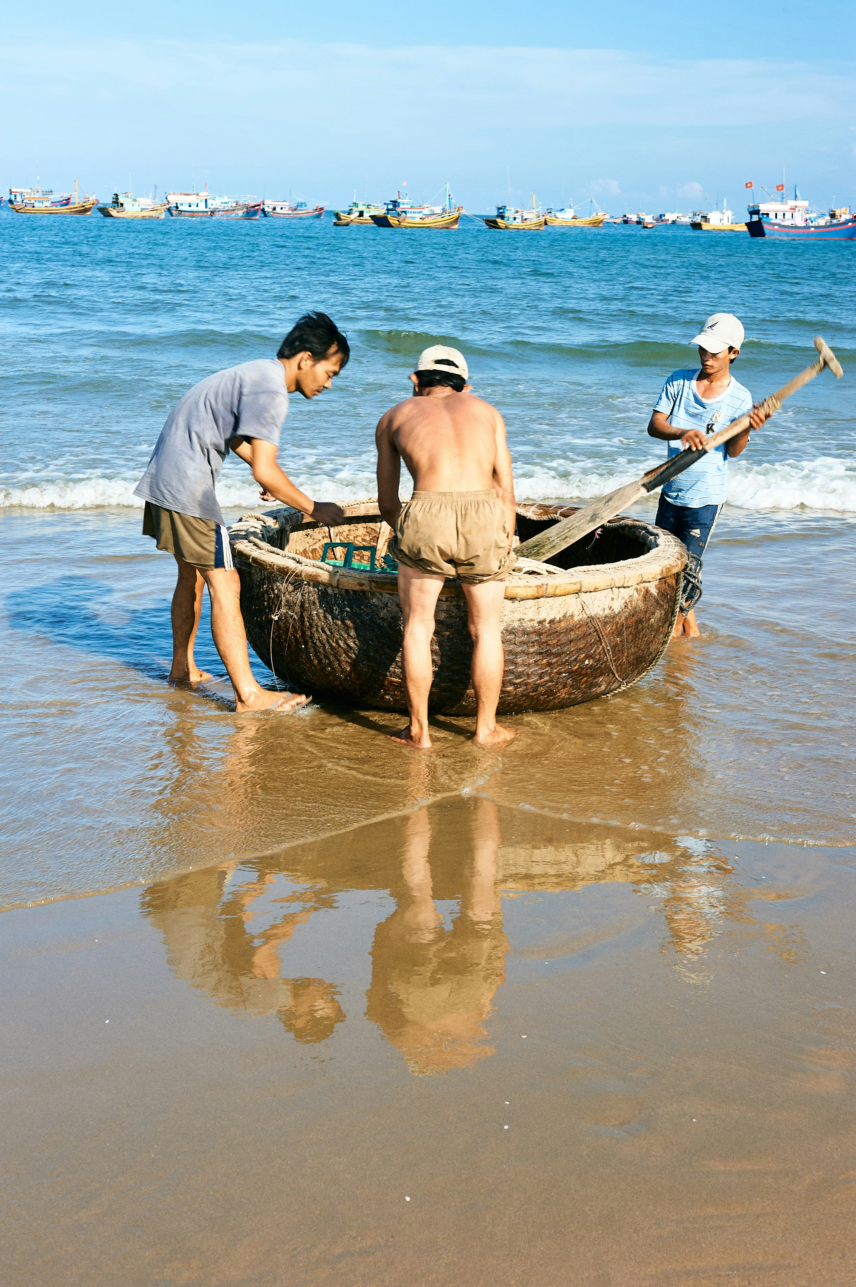 Circling the Tide: Three Fishermen and a Round Boat at the Shore