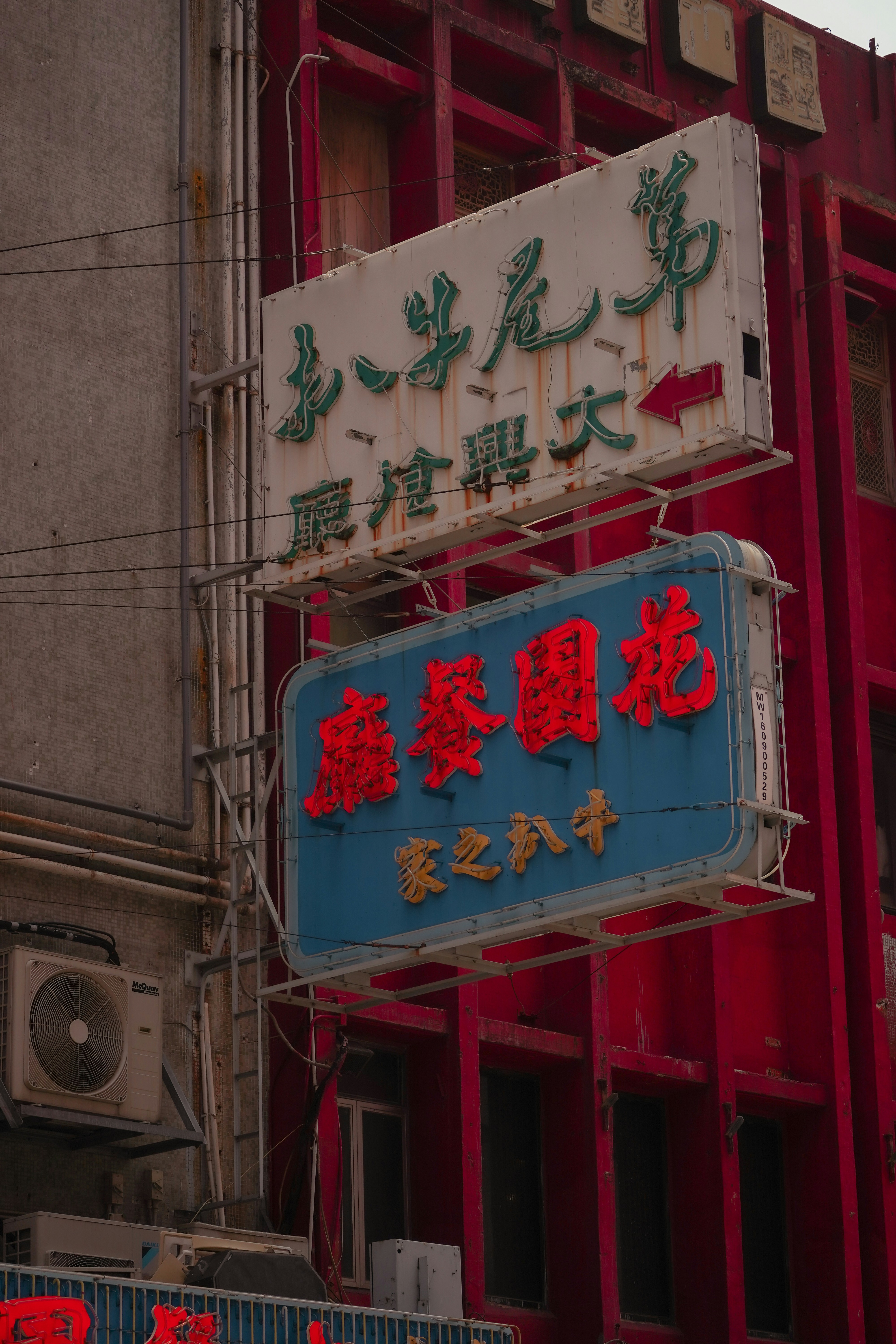 Two illuminated signs on a red building facade.