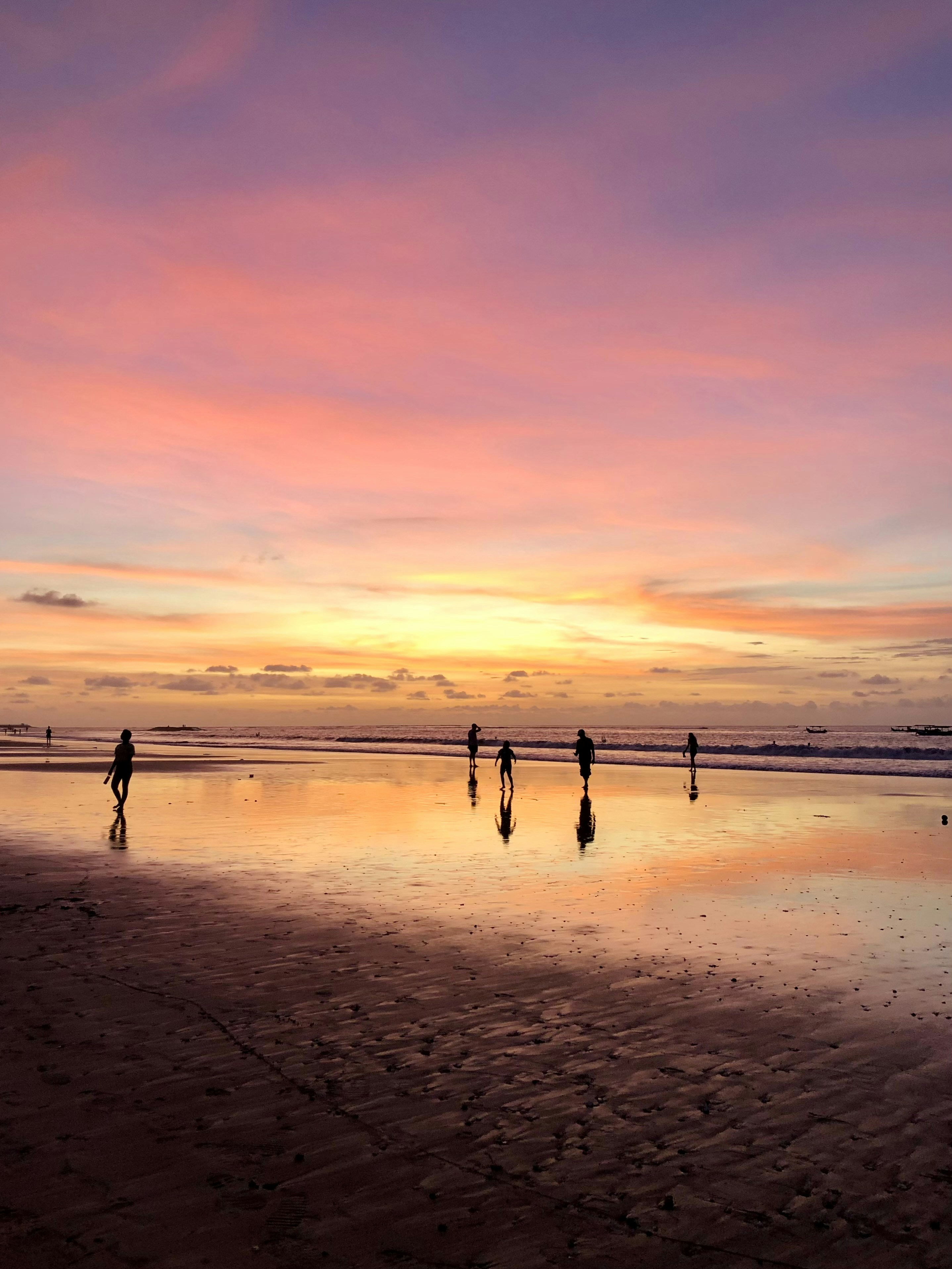 Silhouettes of people walking on a beach during sunset