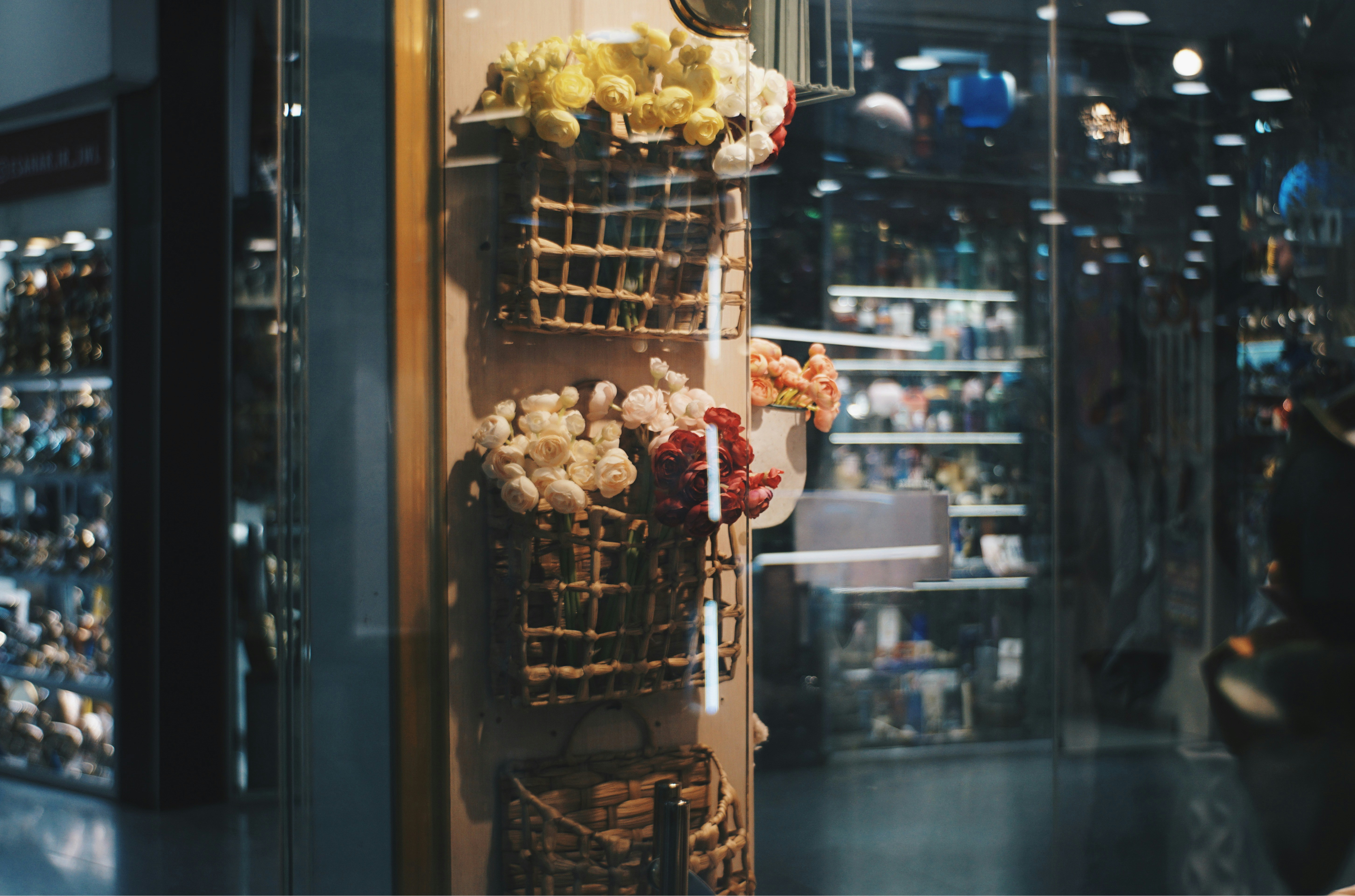 A lovely view through the looking glass. | Two baskets of flowers displayed in a shop window