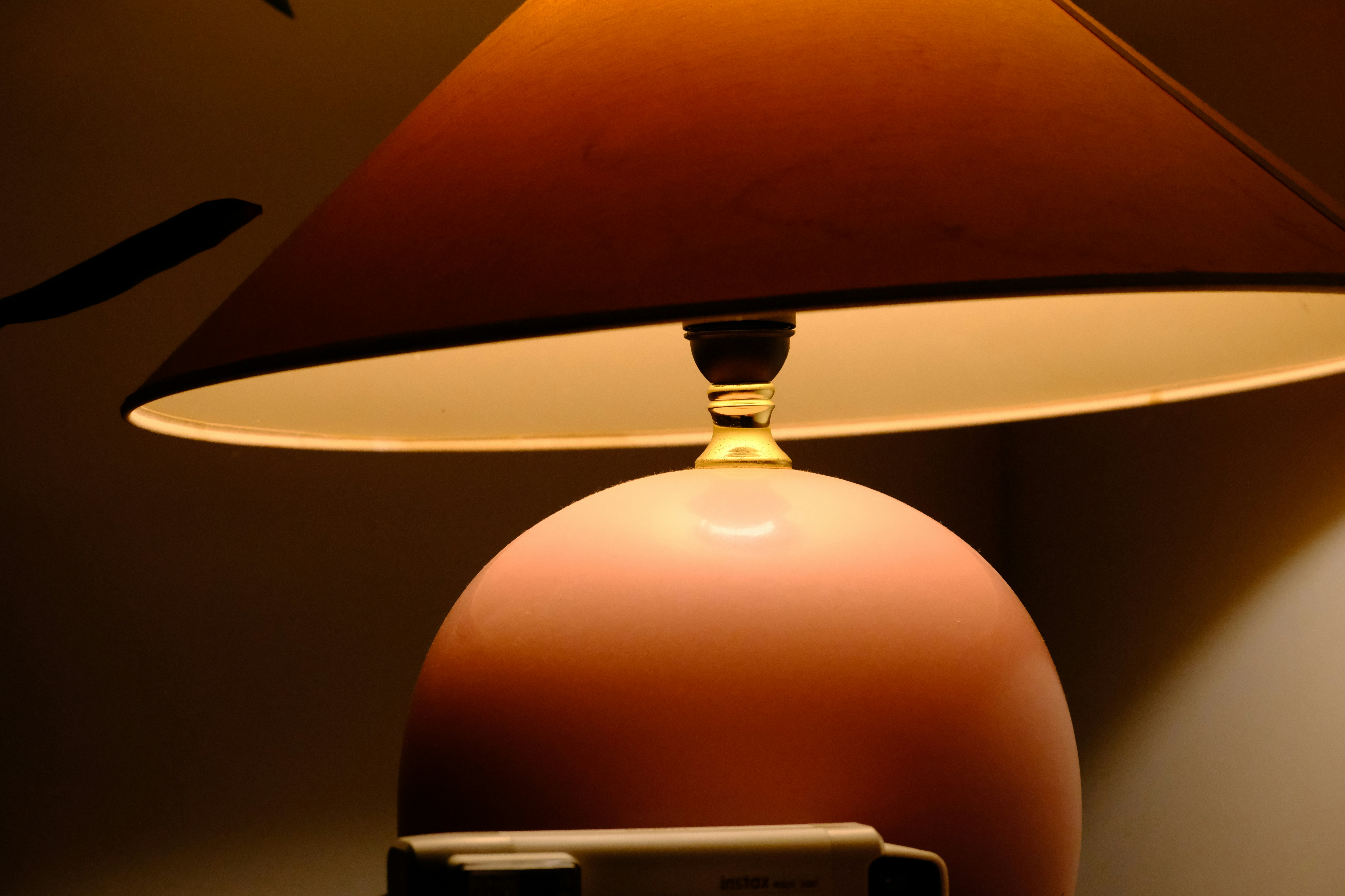 A pink lamp with a brown lampshade glows warmly.