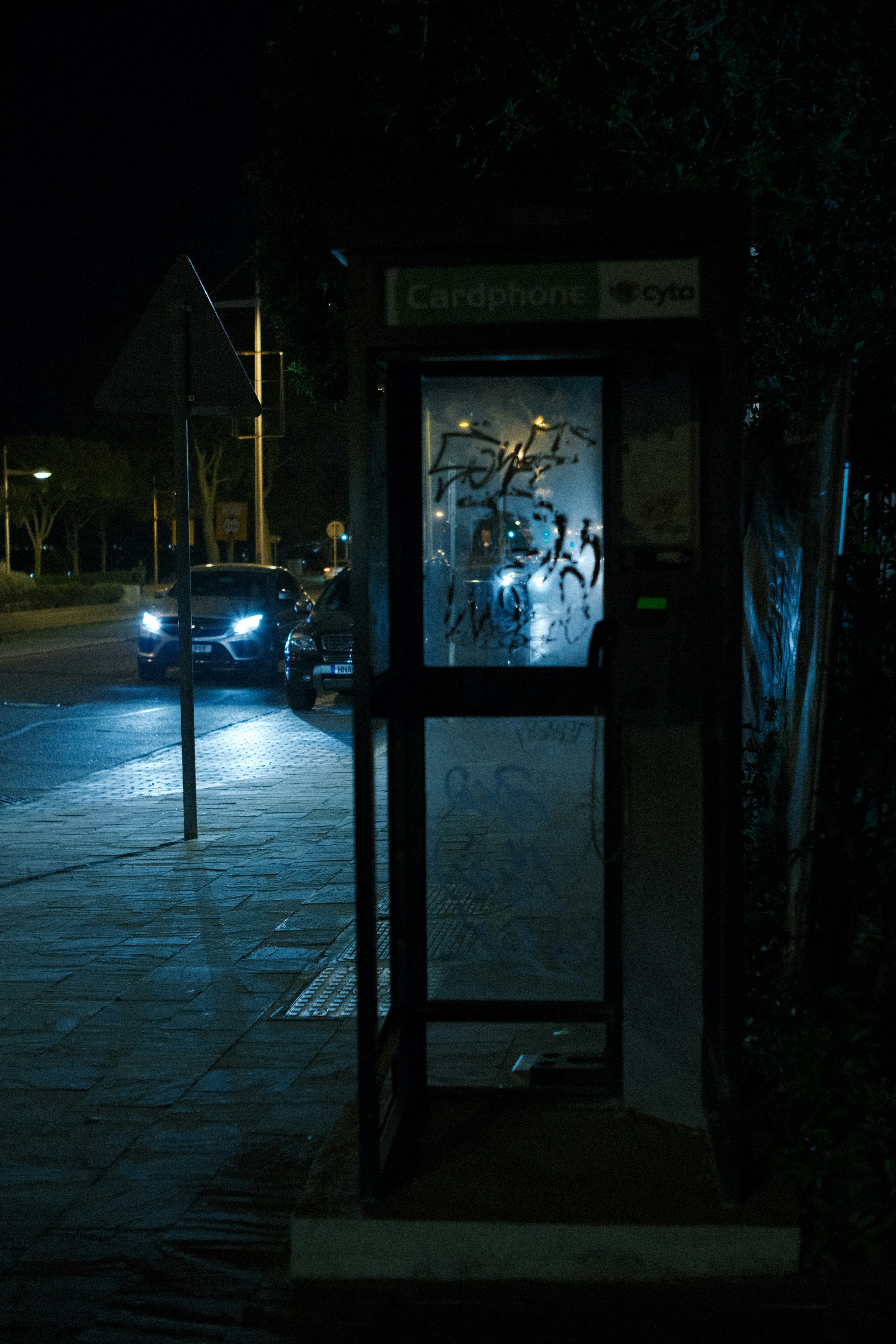 Graffiti-covered phone booth at night with car headlights. photo – Free ...