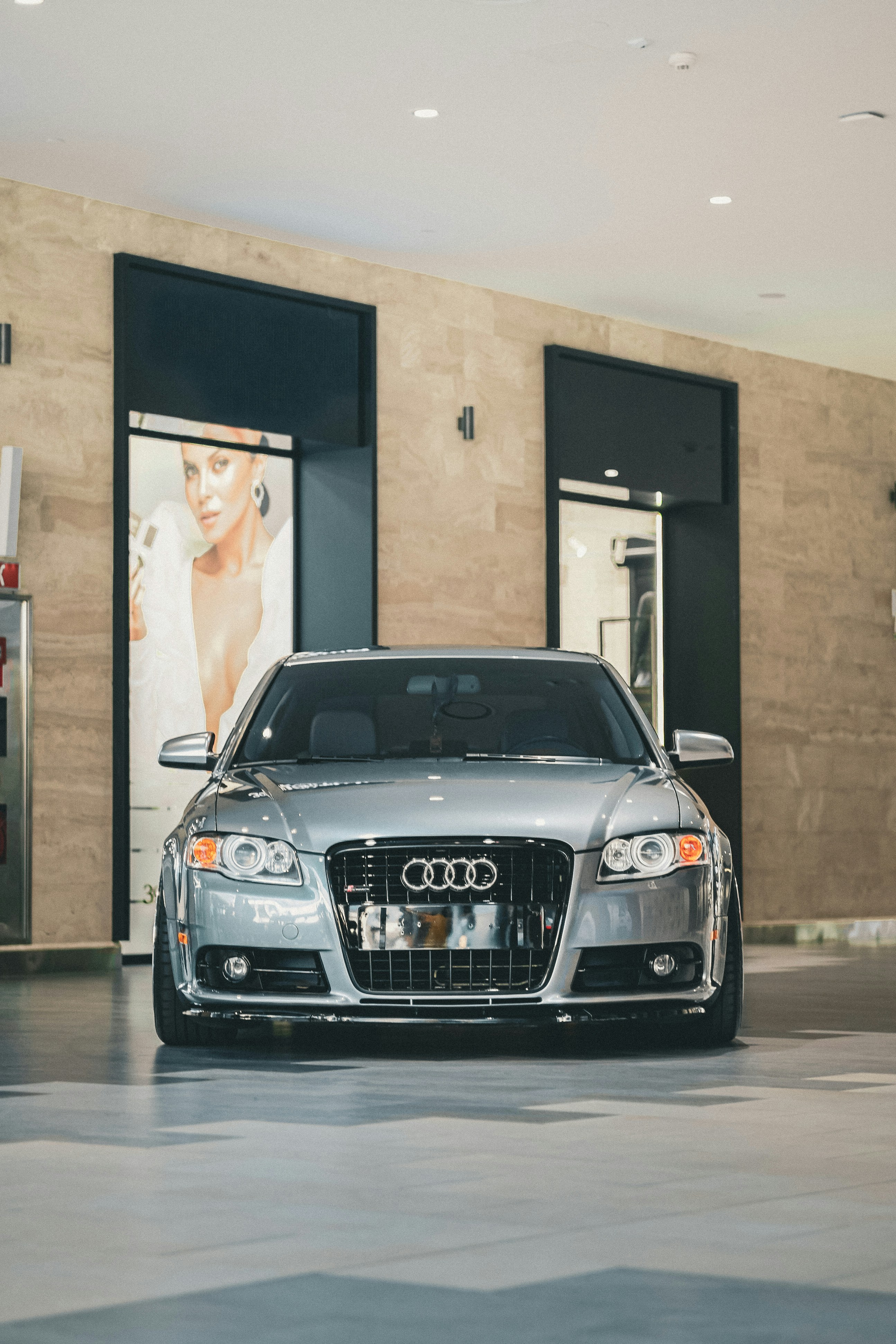 Sleek silver Audi A4 parked in a contemporary shopping area, showcasing its polished exterior against a stylish backdrop.