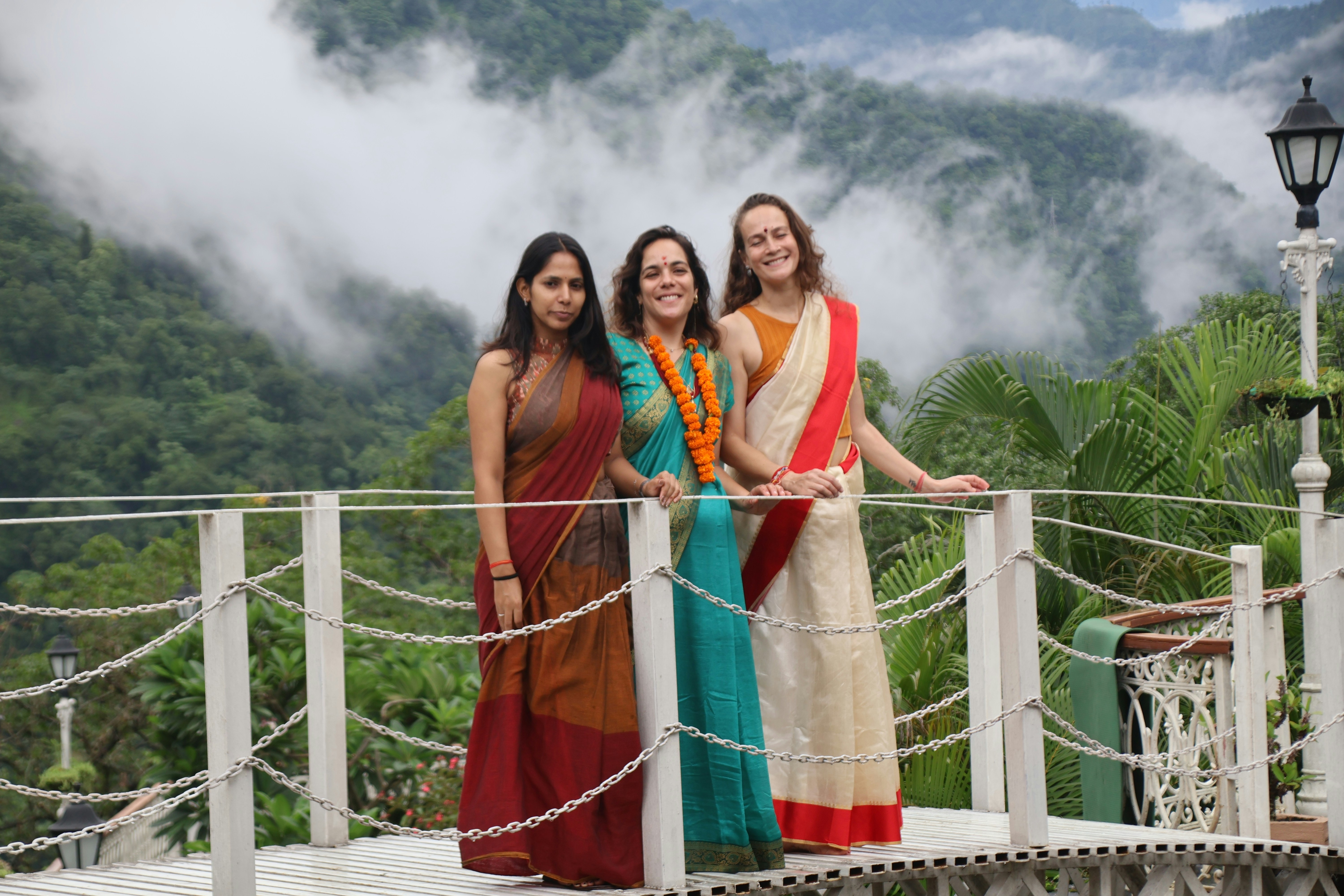 yoga | Three women in saris on a balcony with mountains.