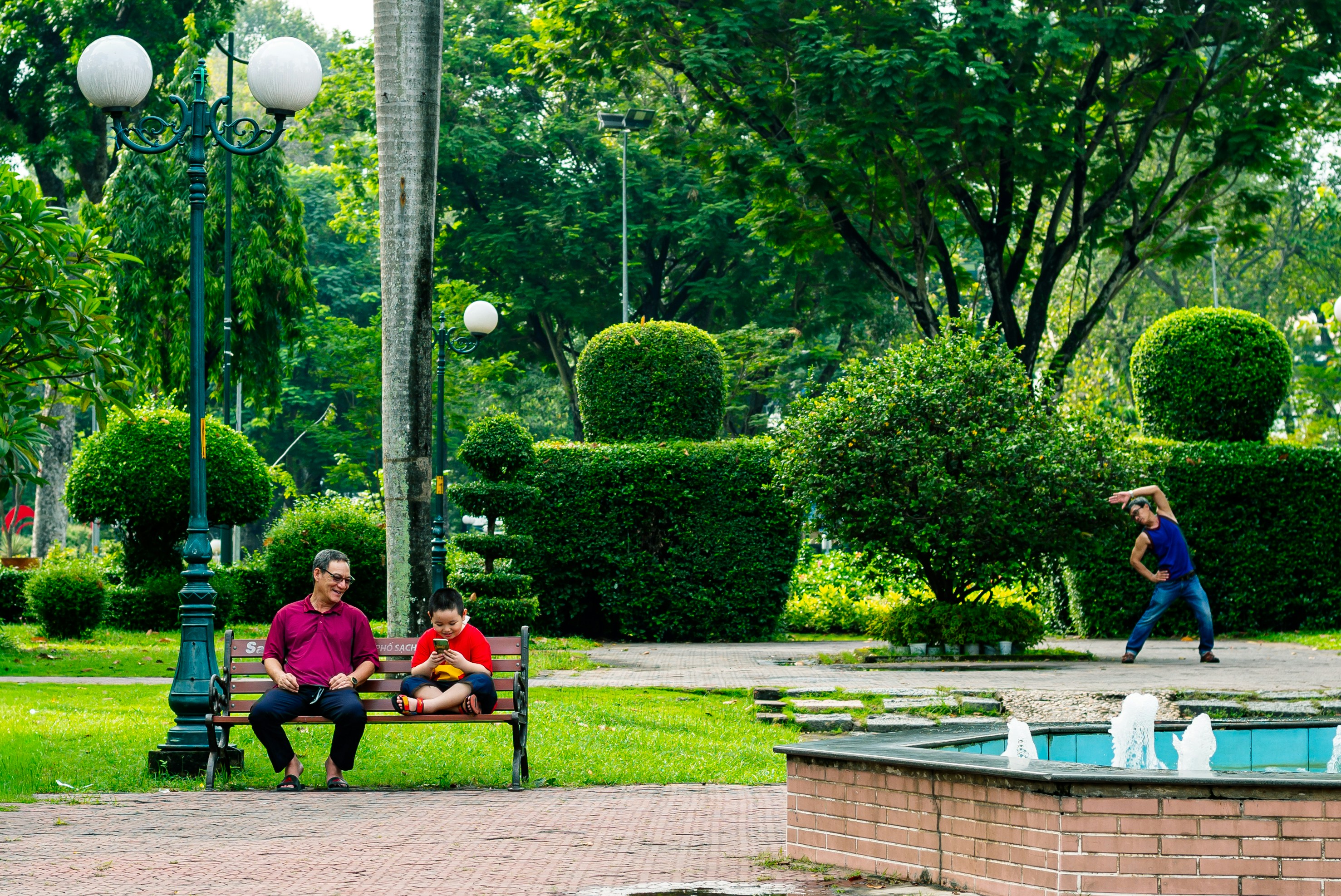 People relaxing in a lush green park with topiaries.