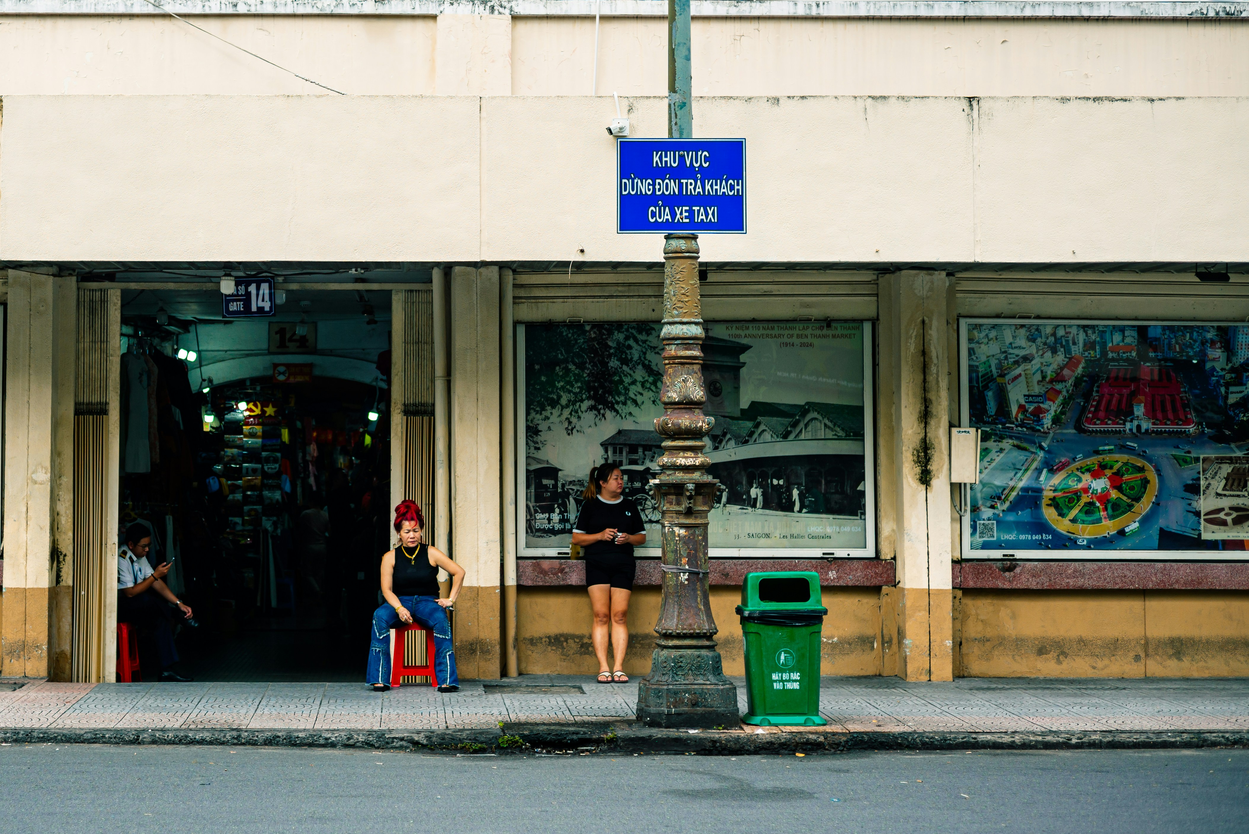 Two women stand near a lamppost on a street.