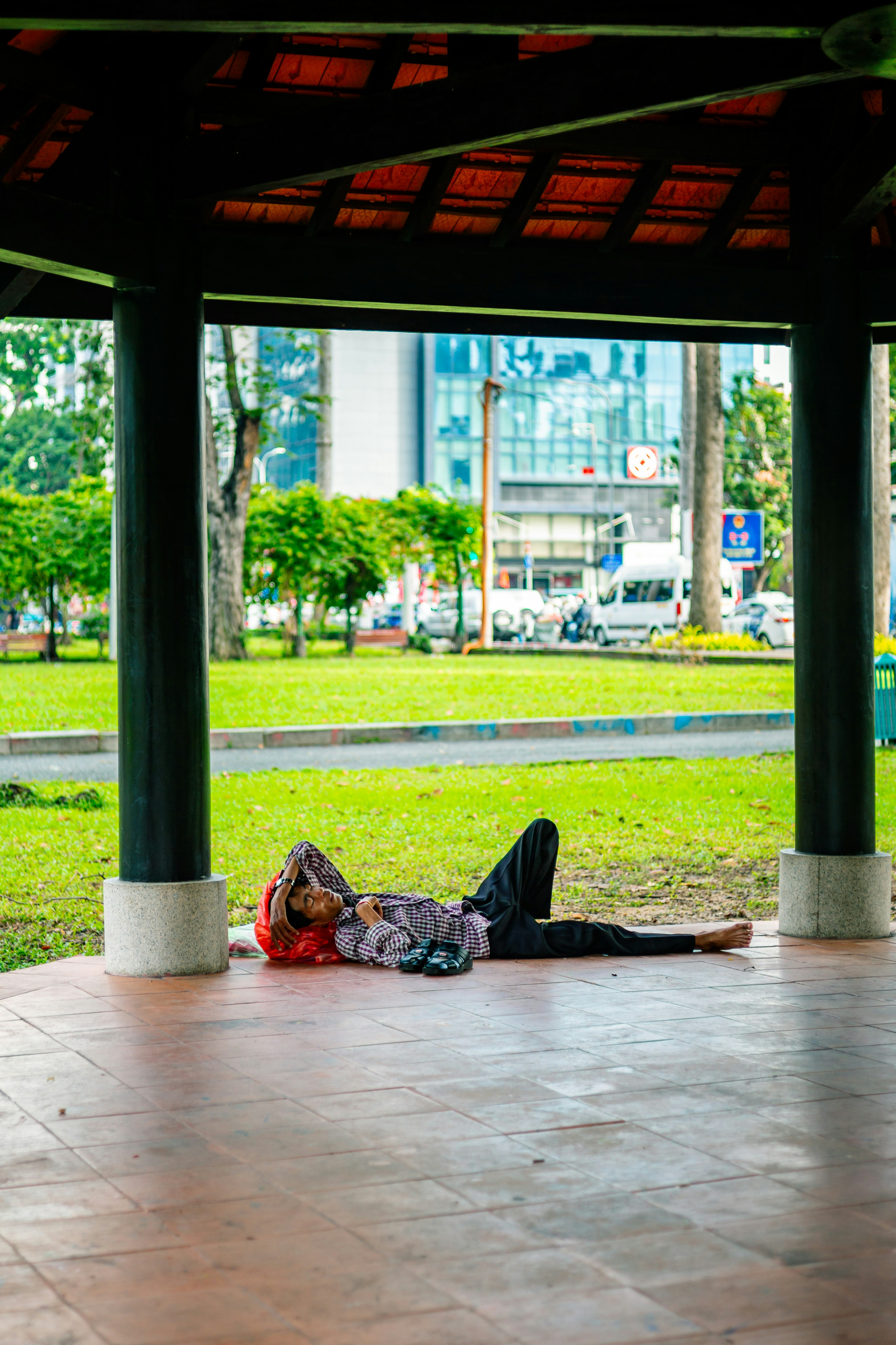 Man resting in a park pavilion with city buildings behind