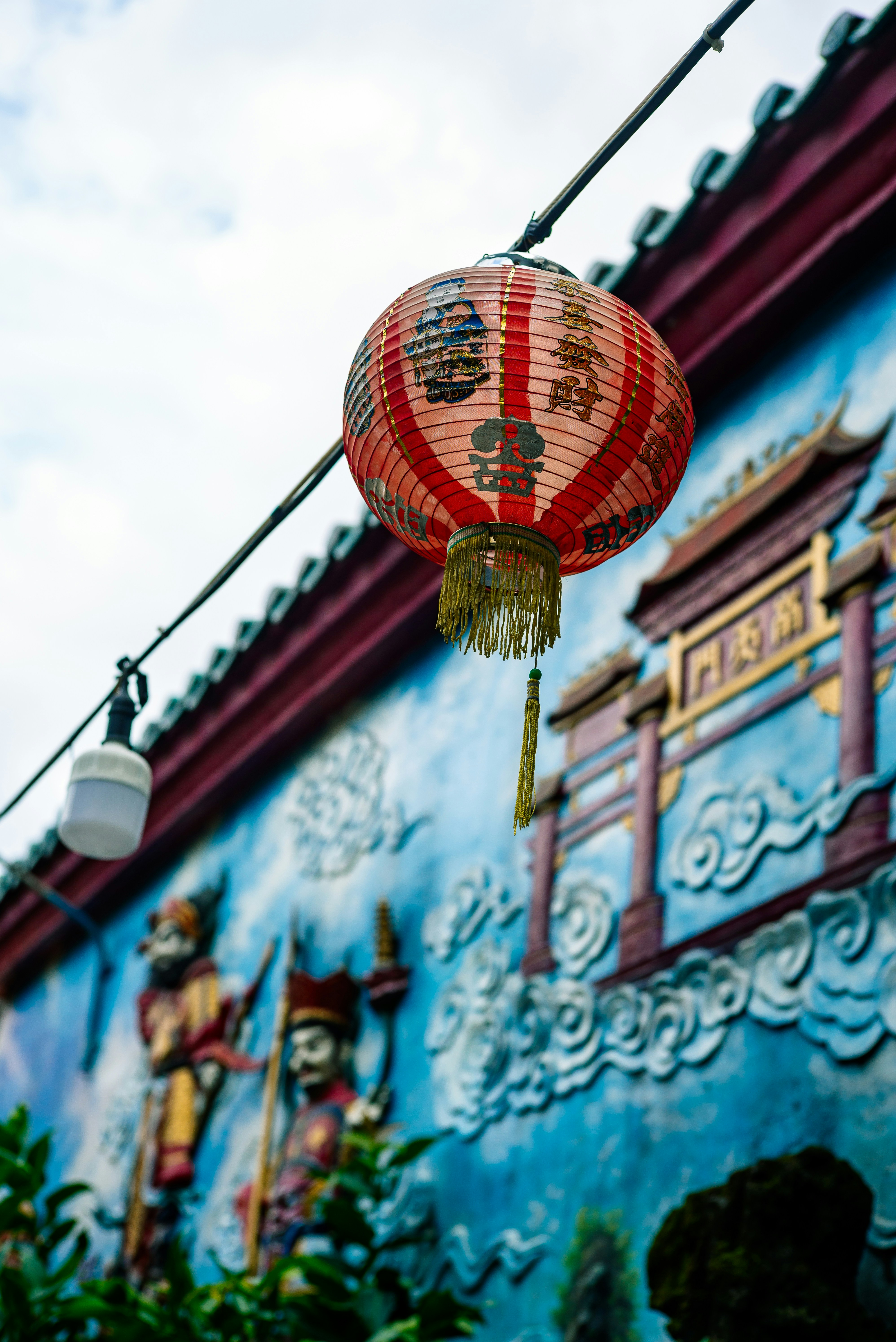 Red lantern hangs in front of colorful mural wall