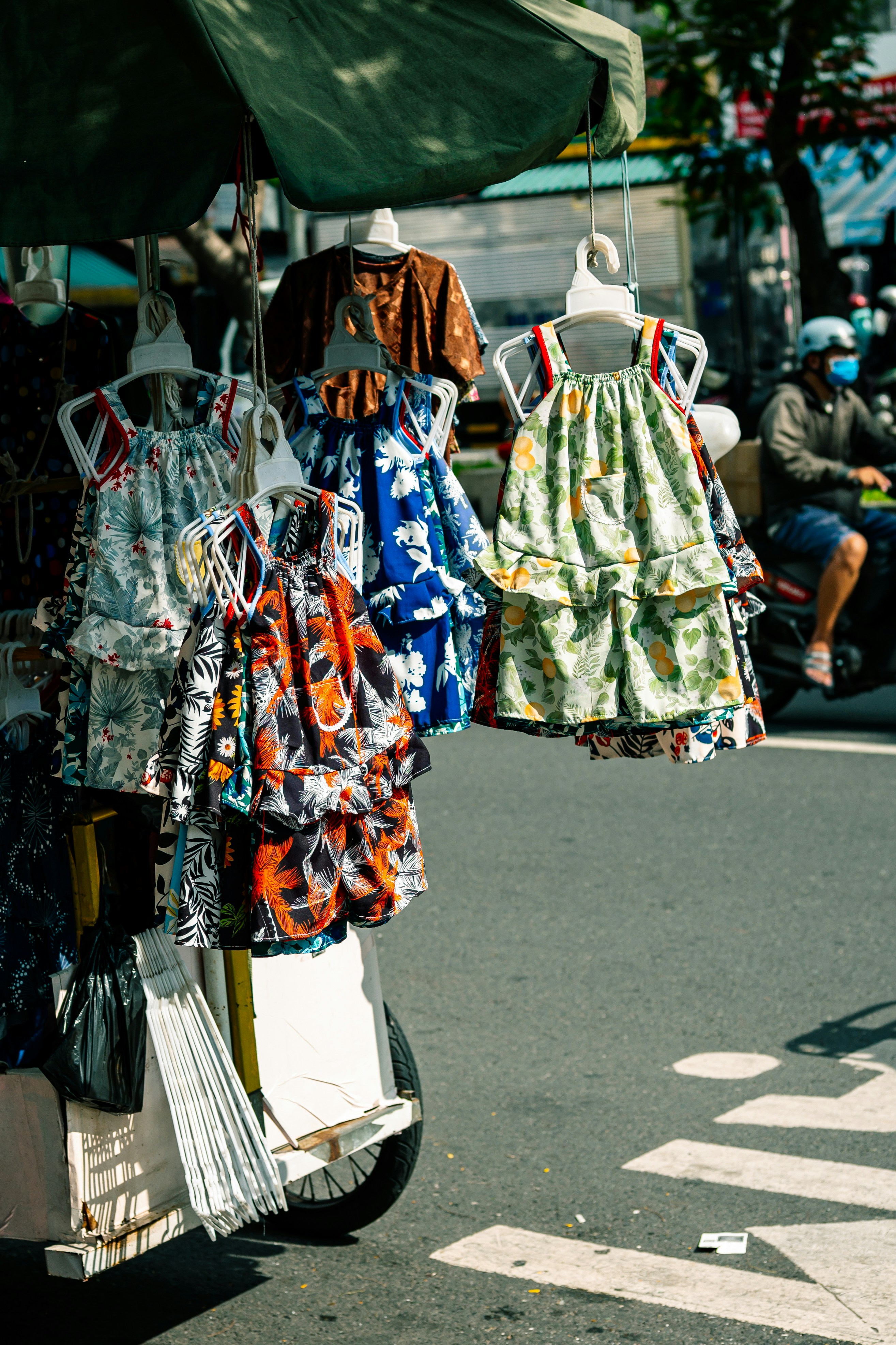 Colorful children's dresses displayed on a street vendor's cart.