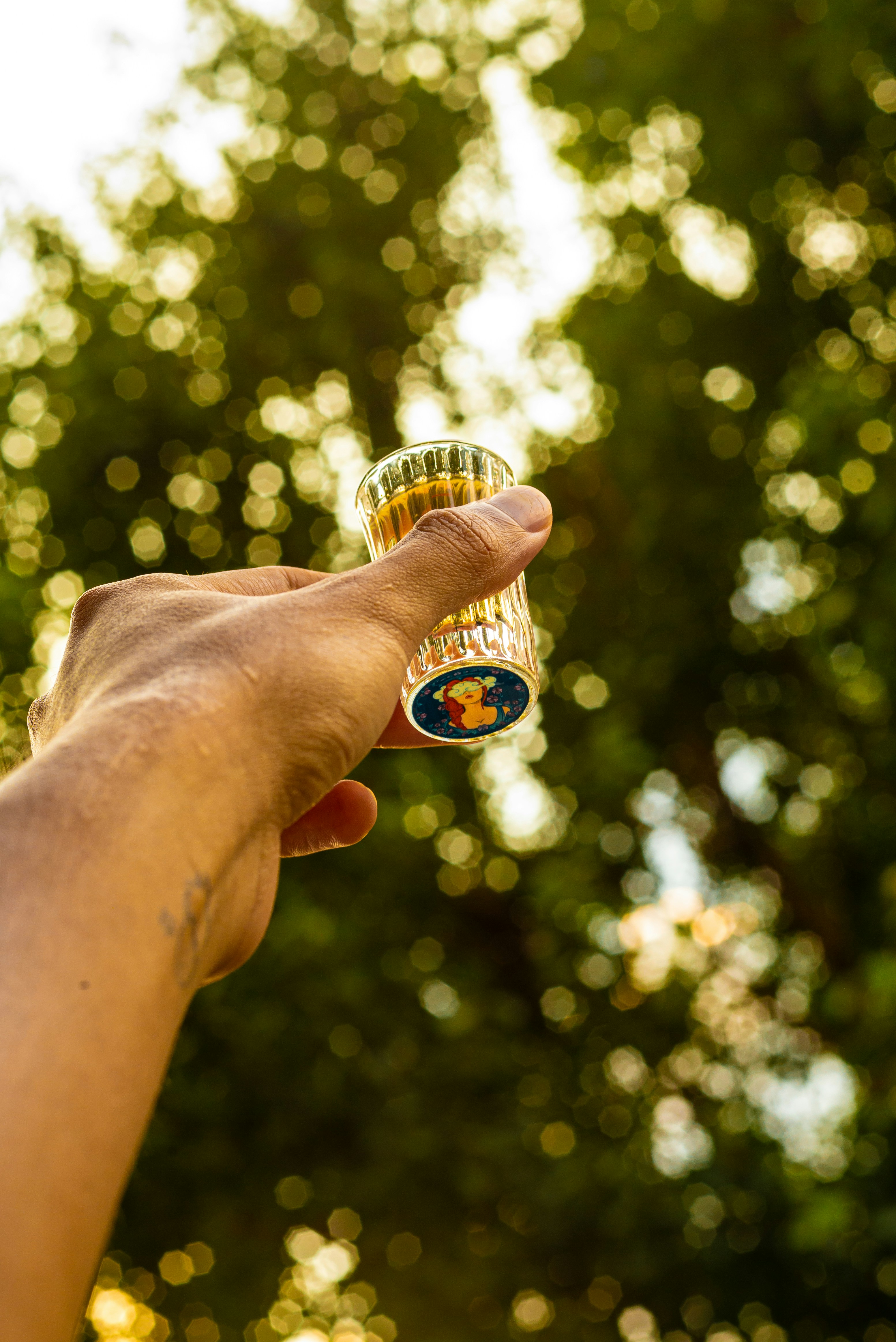 Hand holding a small decorative bottle outdoors.