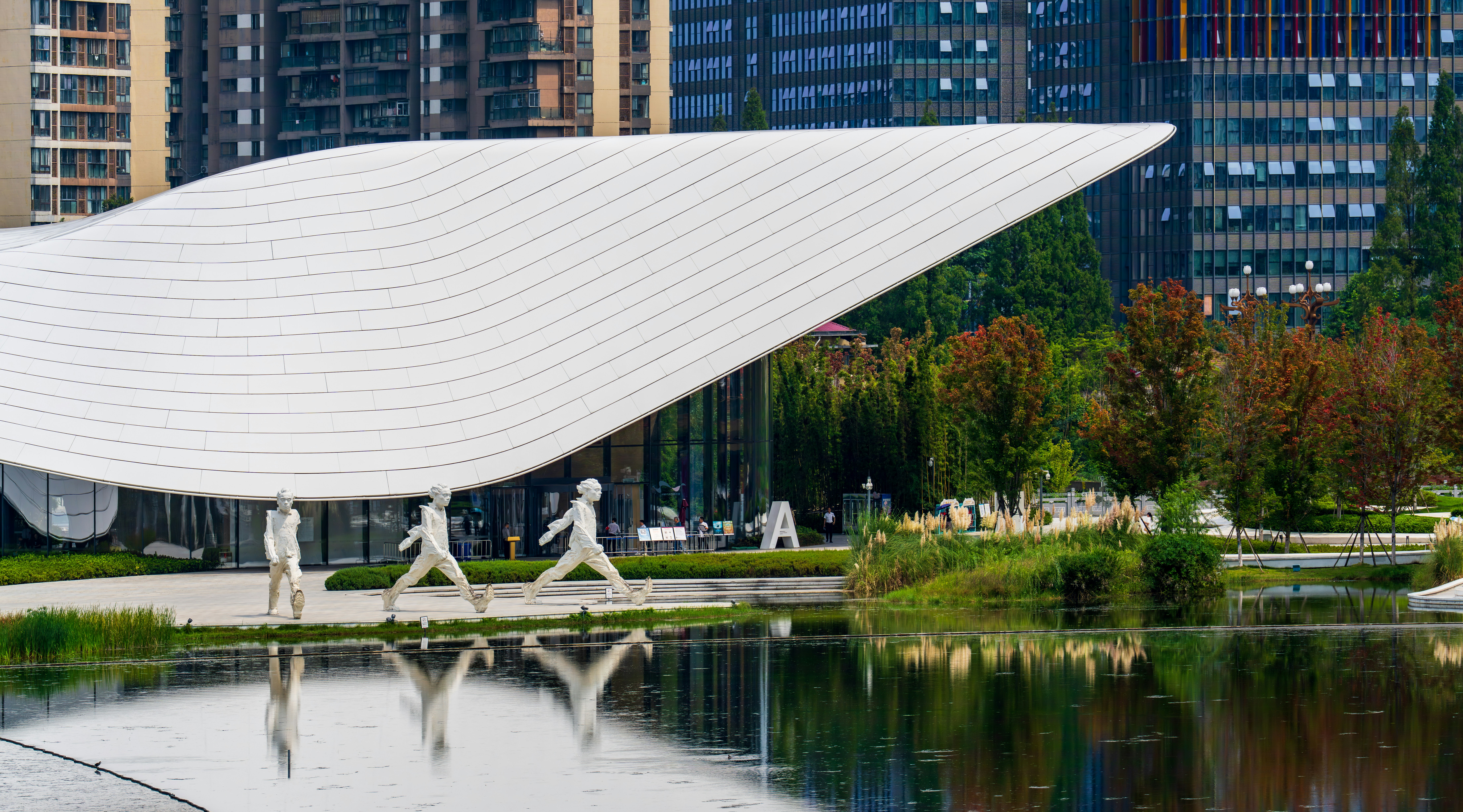 Modern building with reflective water and greenery