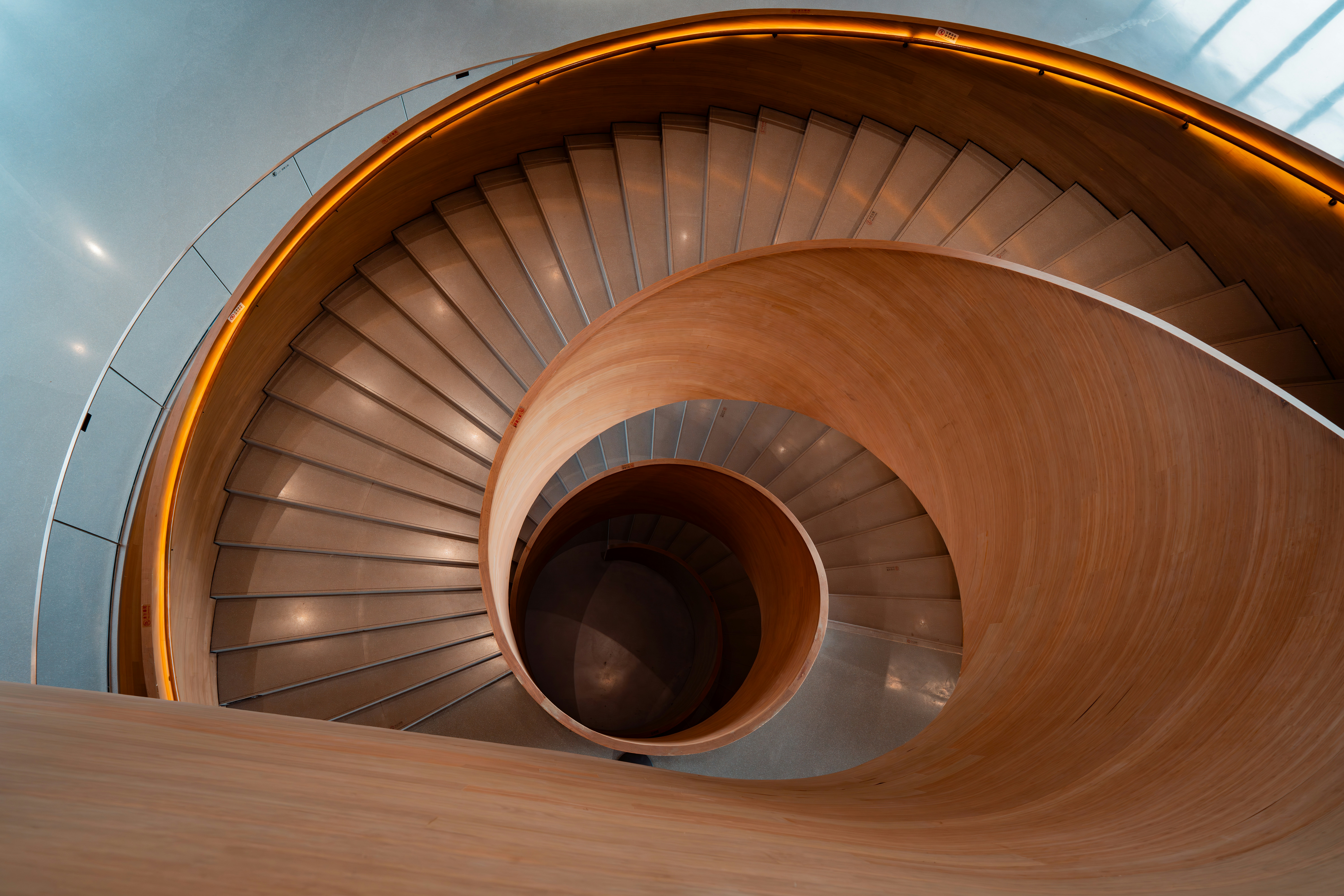 A beautifully crafted wooden spiral staircase with soft lighting, showcasing modern architectural elegance and intricate design elements.
