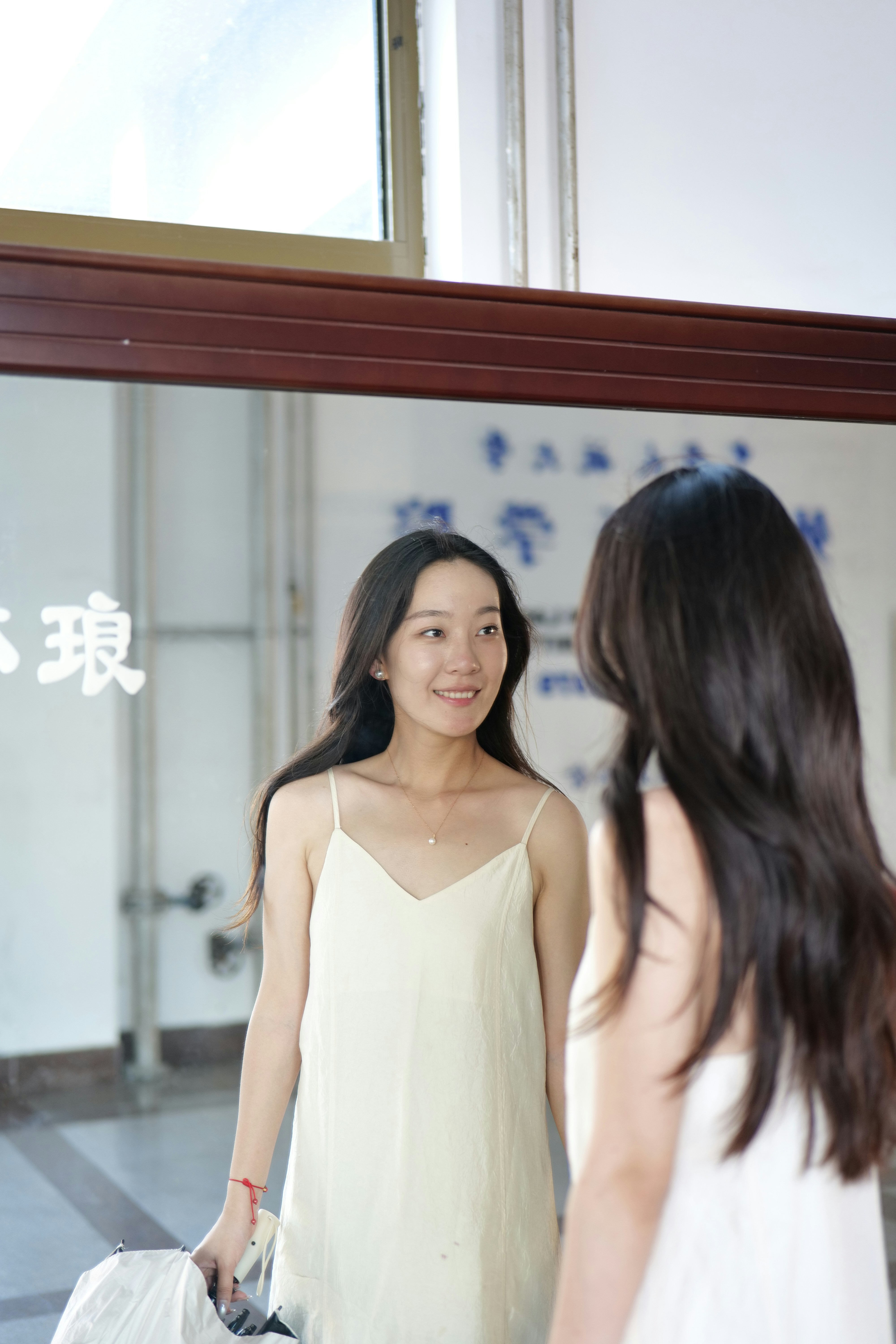 Young woman in white dress smiles at reflection