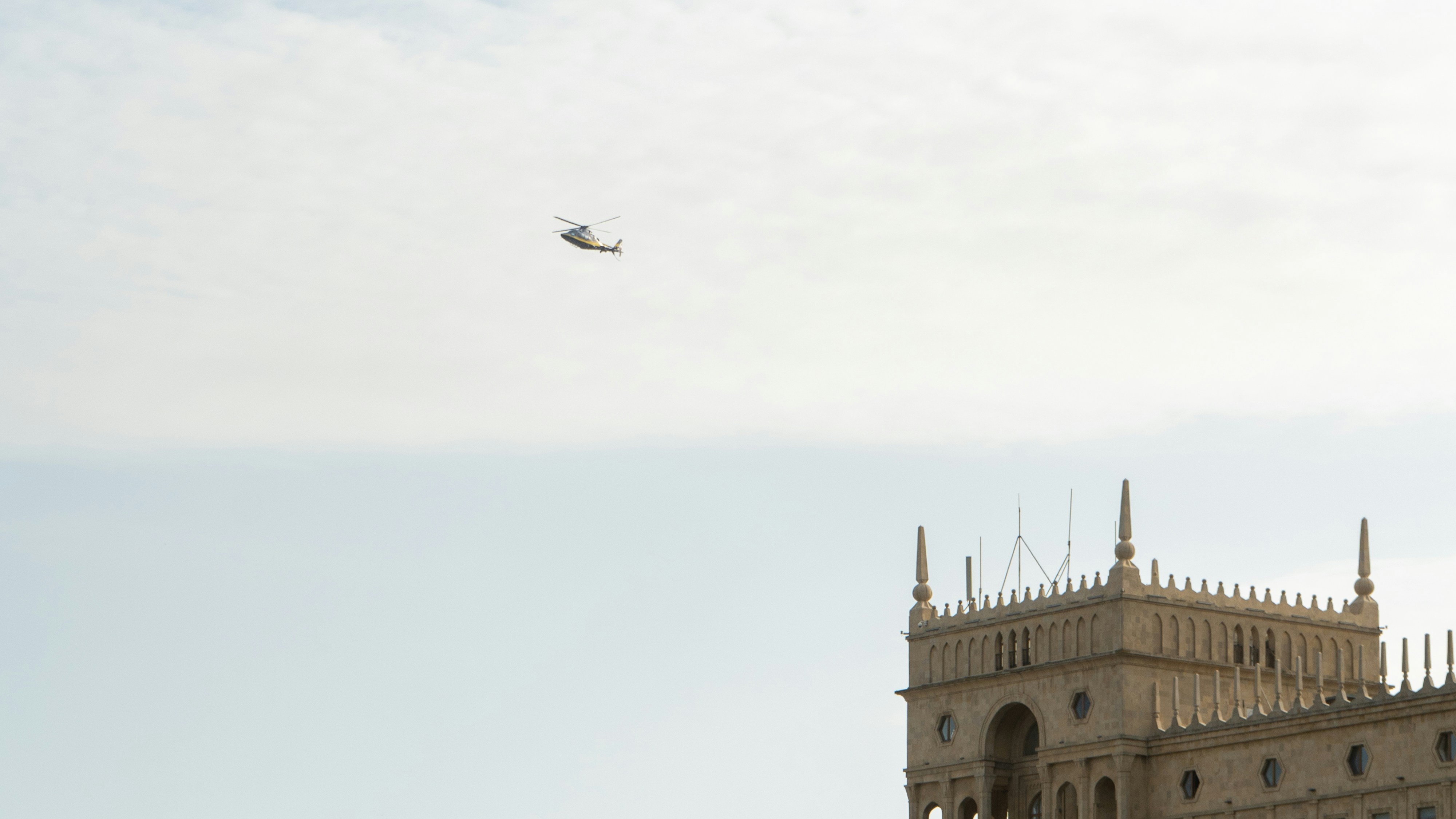 Helicopter flies over ornate building facade.