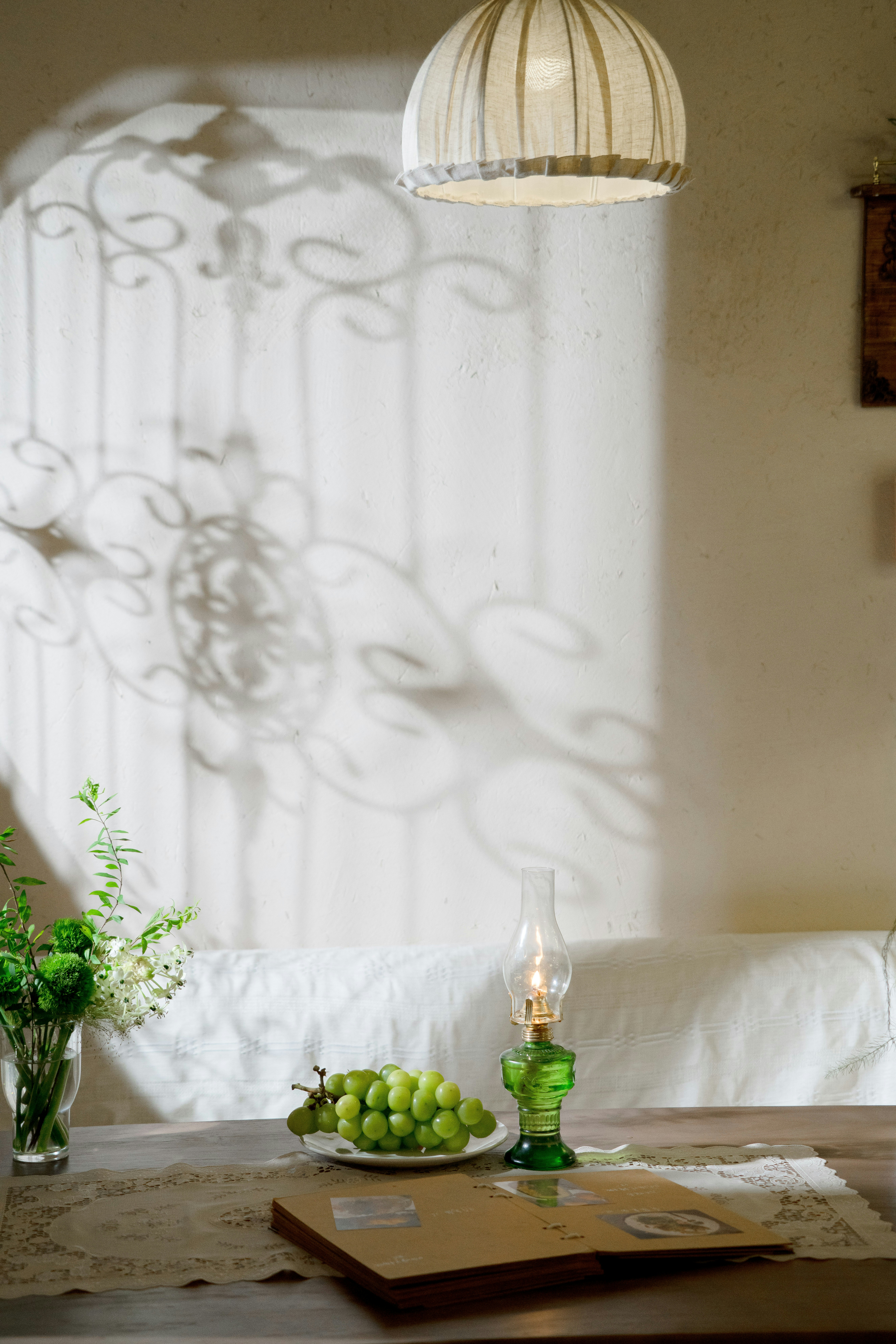 Grapes and lamp cast shadows on a wall.