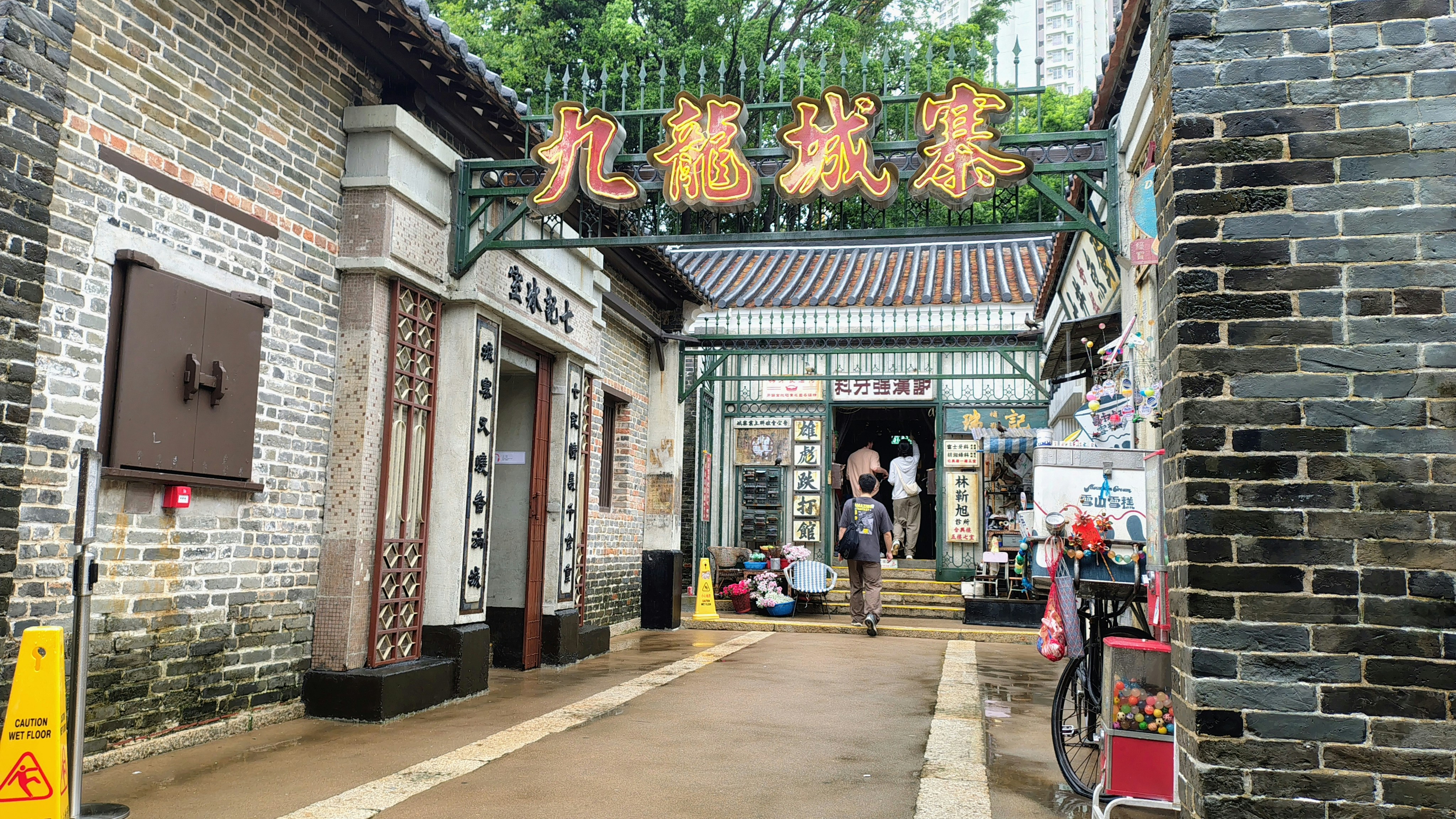 Entrance to the Kowloon Walled City Park museum, Hong Kong | Traditional buildings with a neon sign in an alley.
