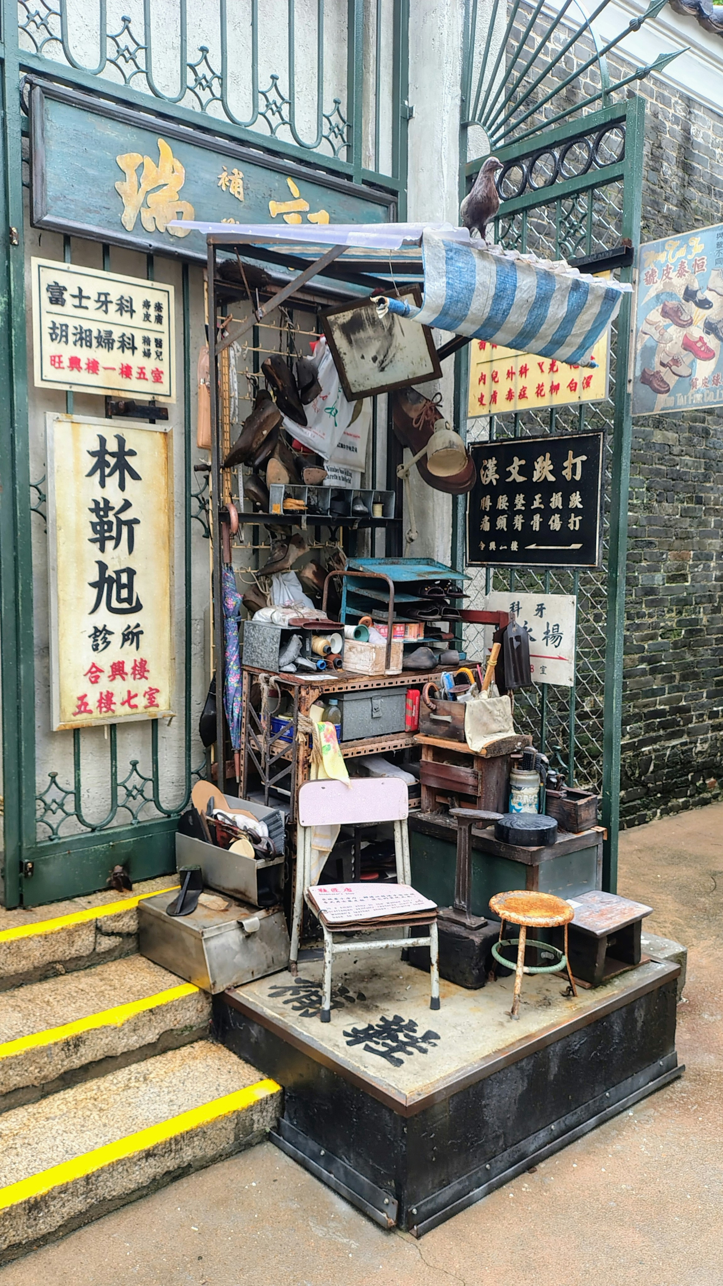 Kowloon Walled City museum, Hong Kong | Small shop with tools and signs, a chair and stools.