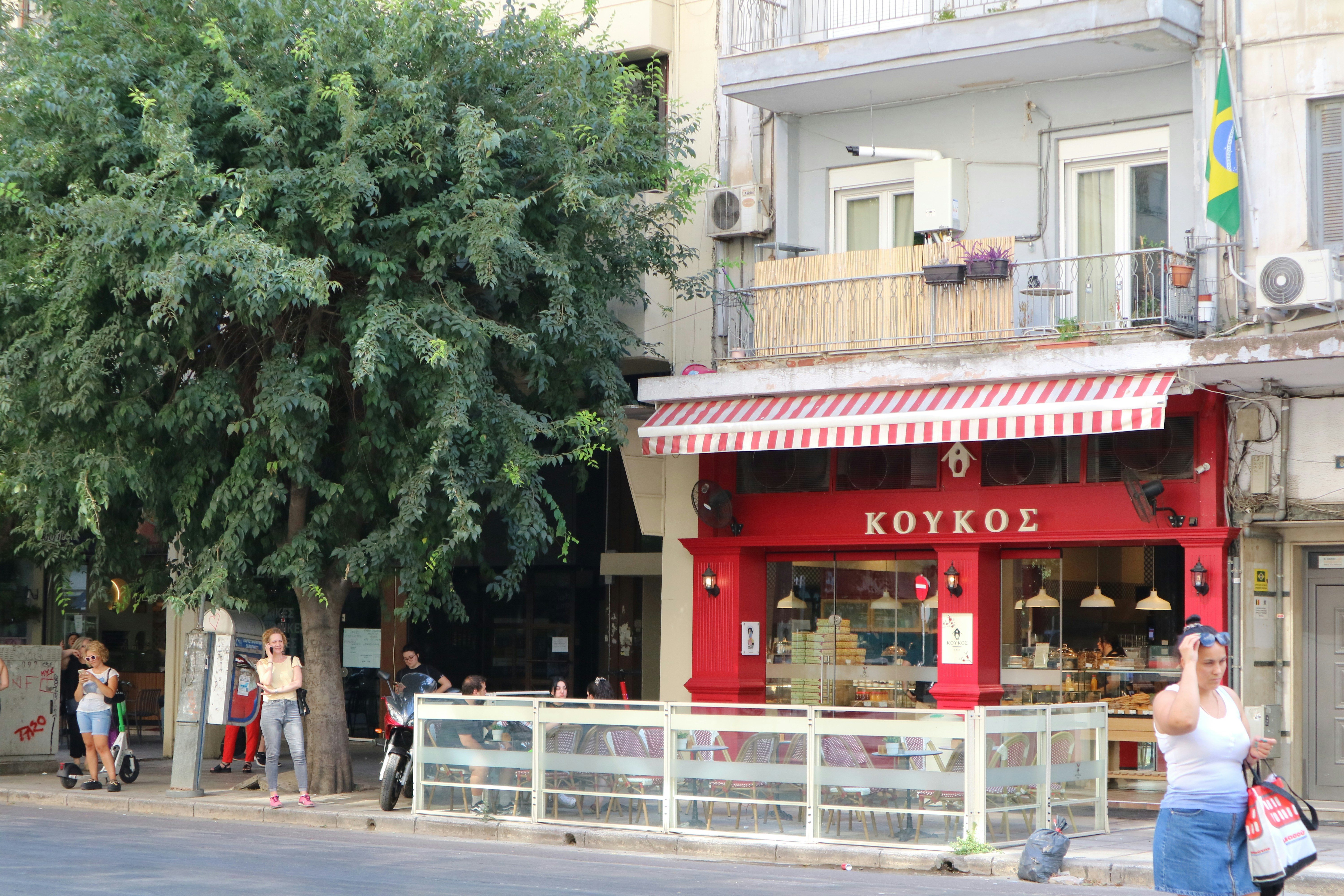 Red storefront with greek writing and outdoor seating