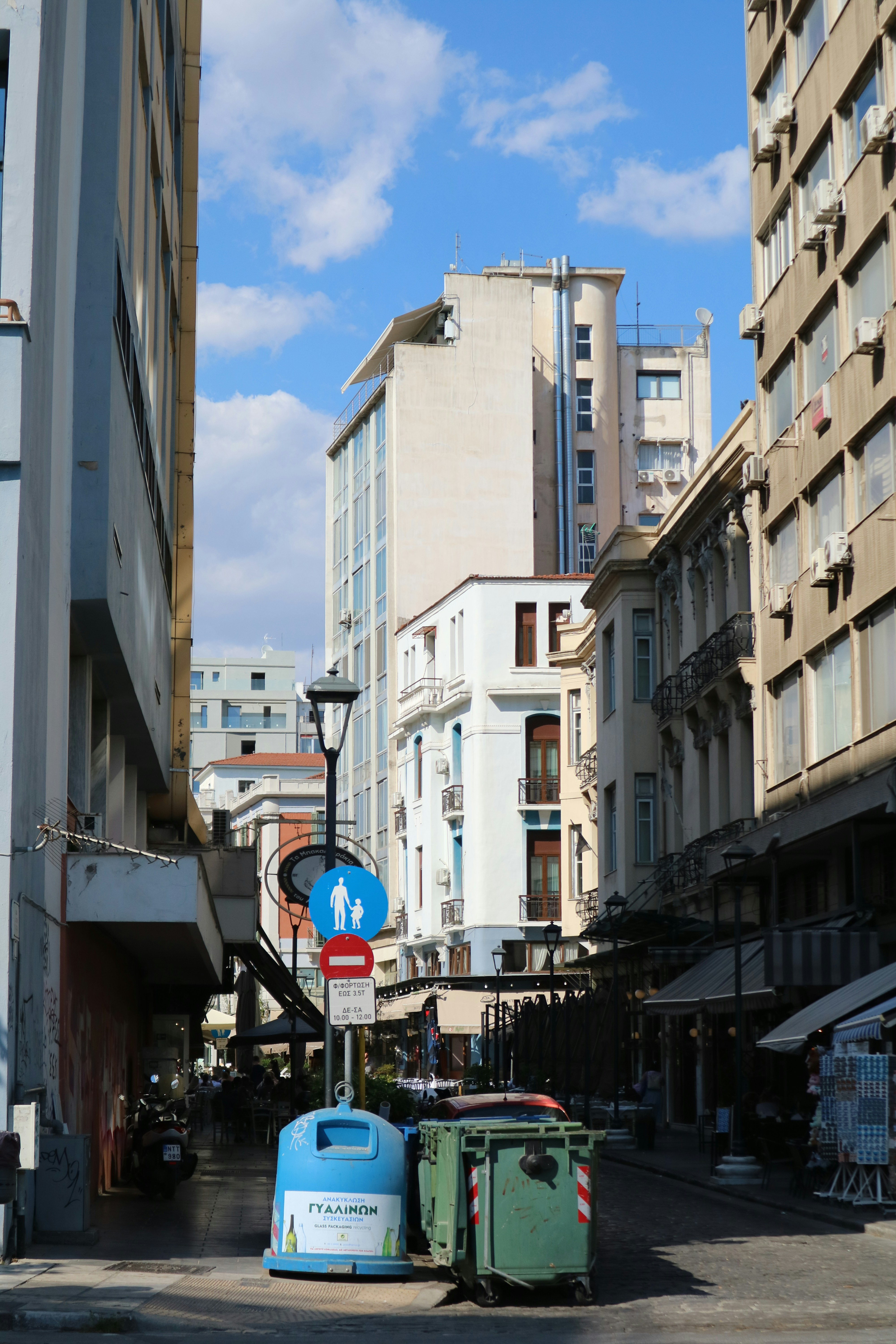 Street scene with buildings, signs, and trash bins.