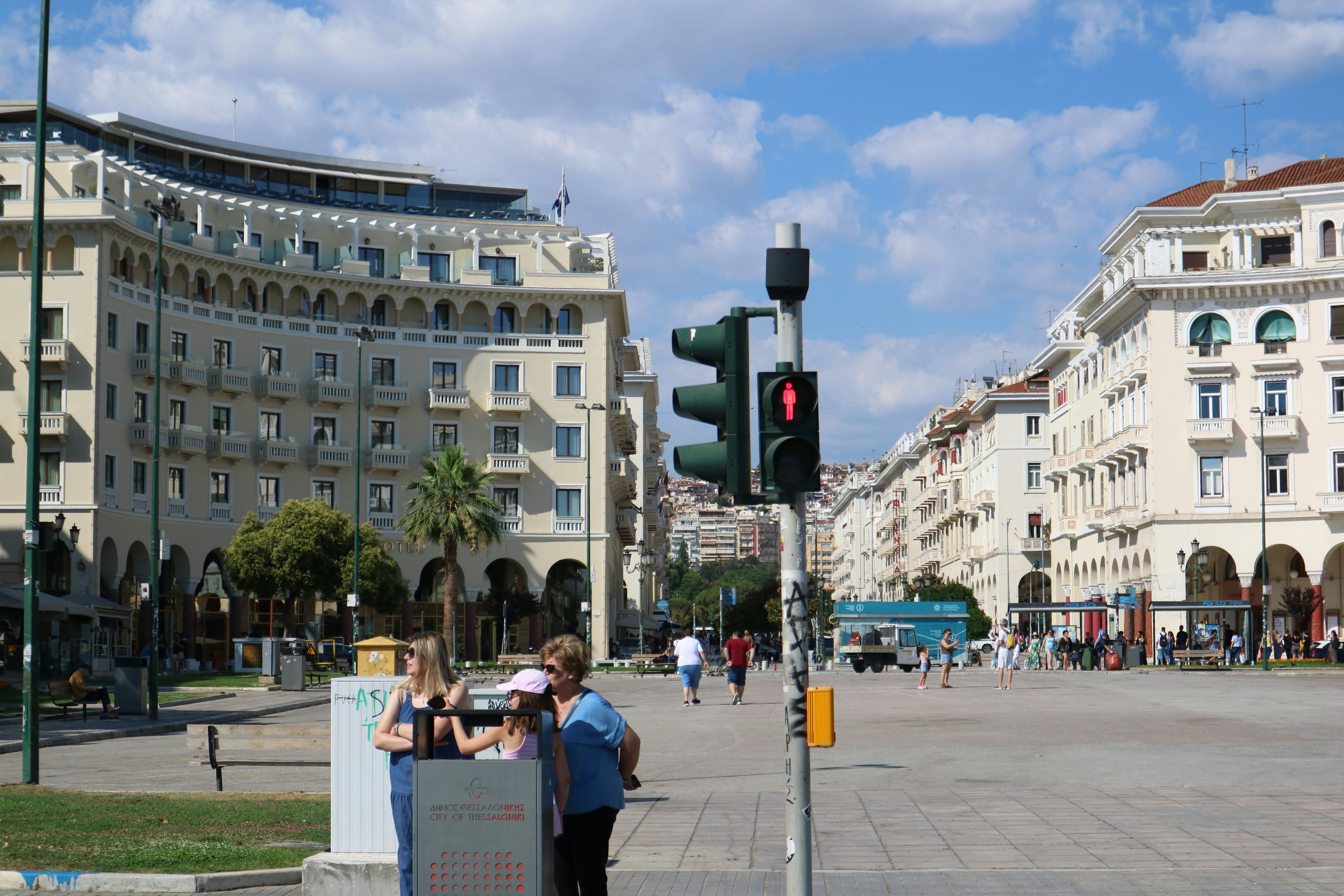 People in a city square with buildings and traffic light.