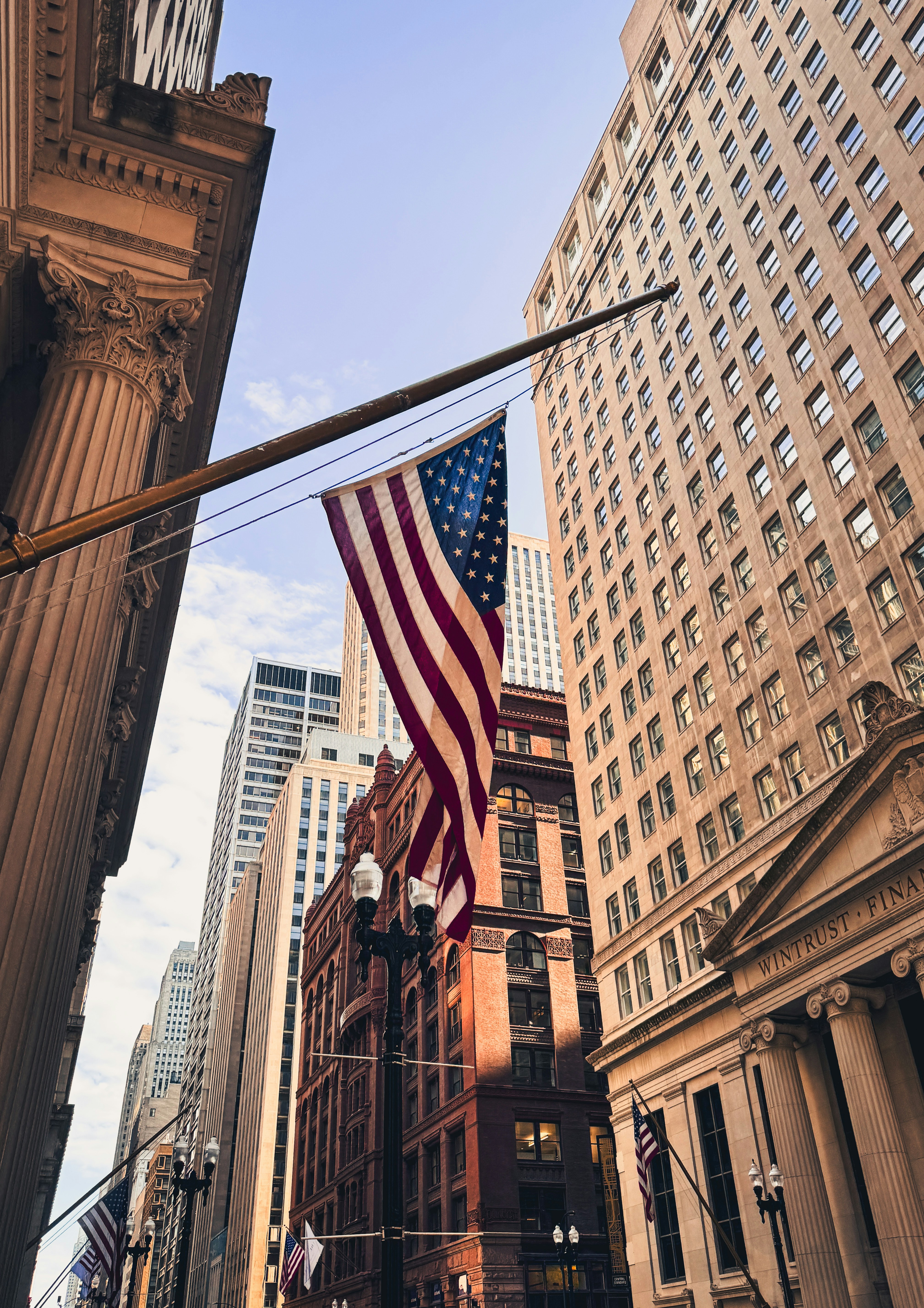 American flag hangs between tall buildings in city.