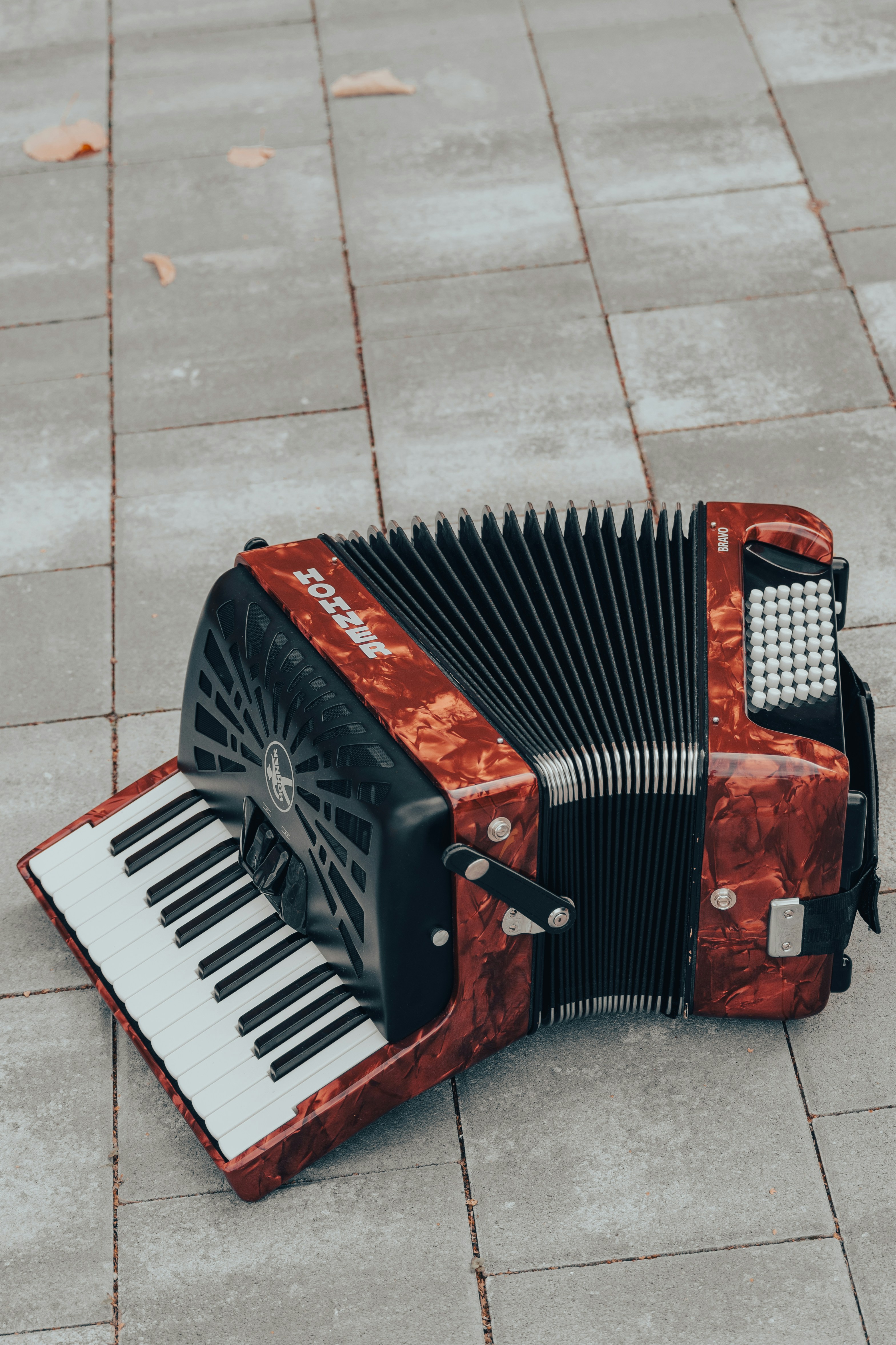 Red accordion resting on a stone patio.