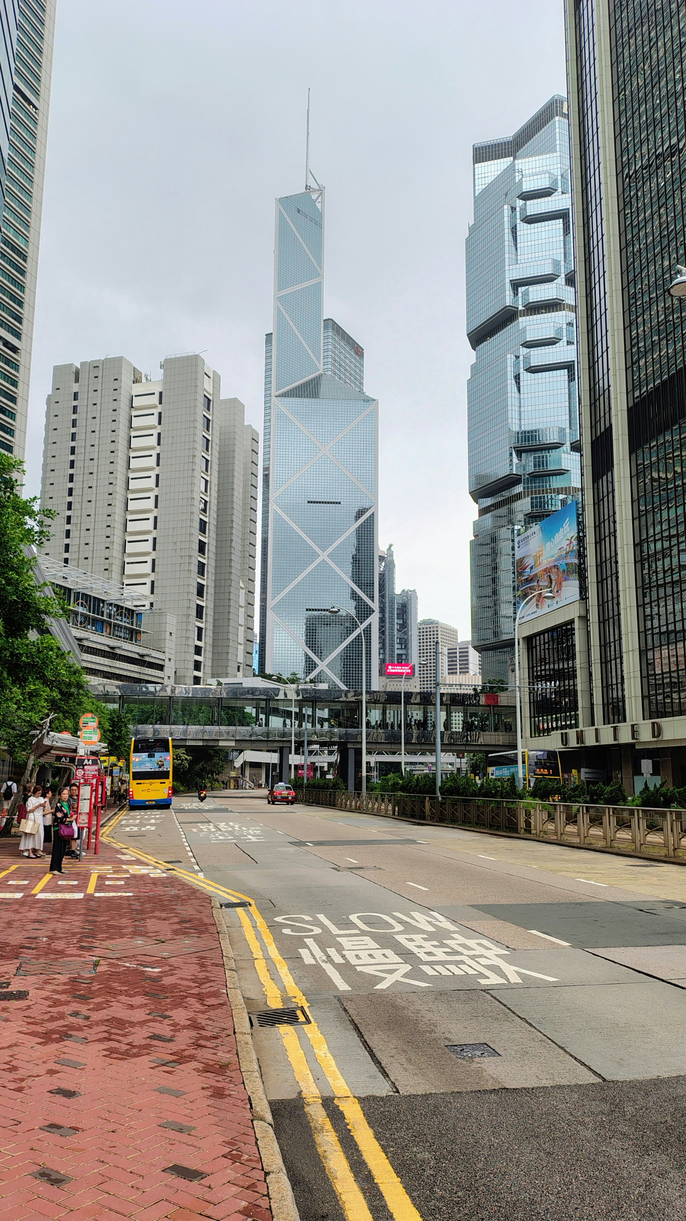 Bank of China tower, Hong Kong | Modern skyscrapers line a city street with a bus.