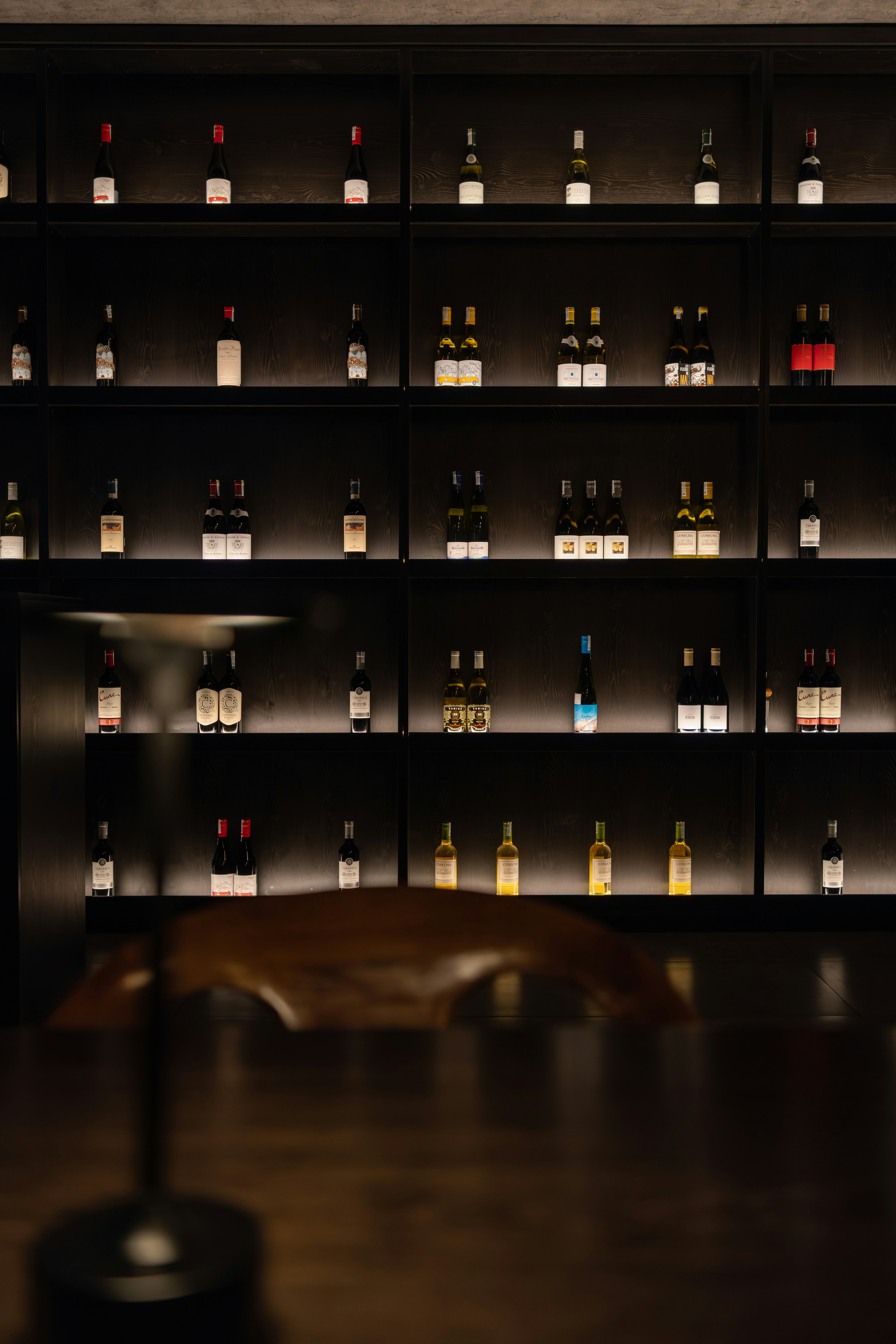 Wine bottles displayed on shelves in a dimly lit cellar.