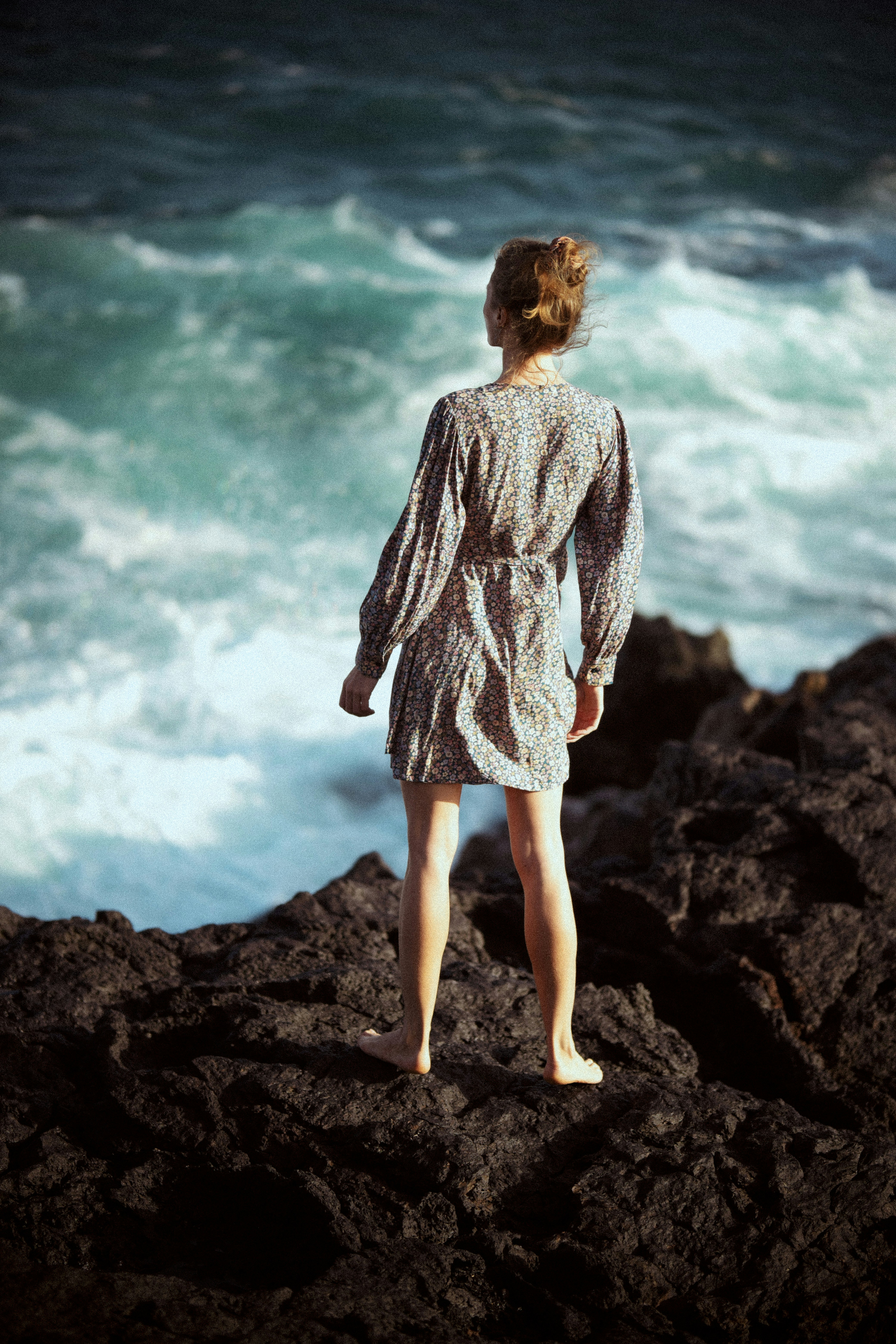 Woman standing on rocks by the ocean