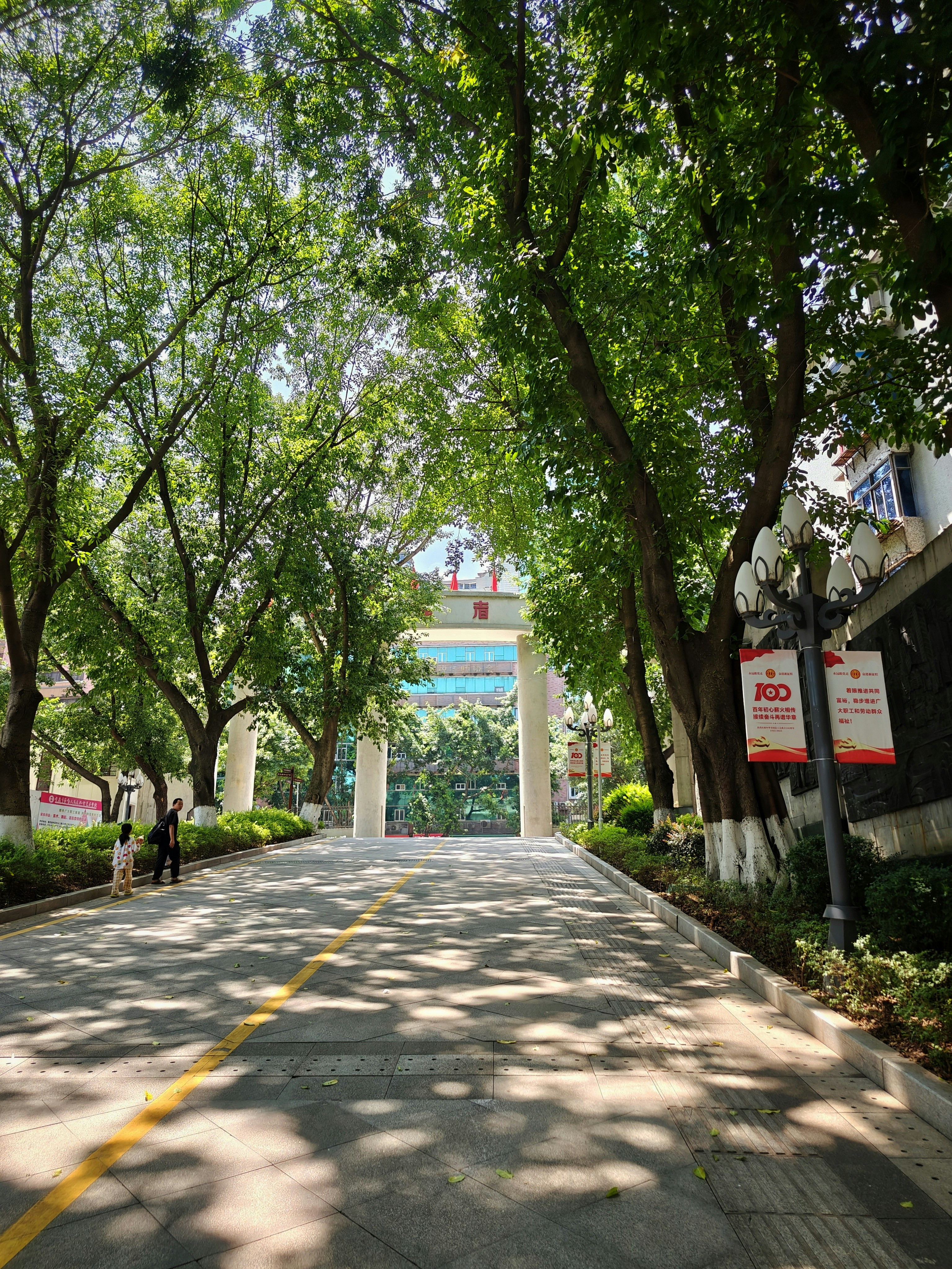 Entrance to the Cultural Palace Central Square. | Tree-lined pathway leads to a building entrance.