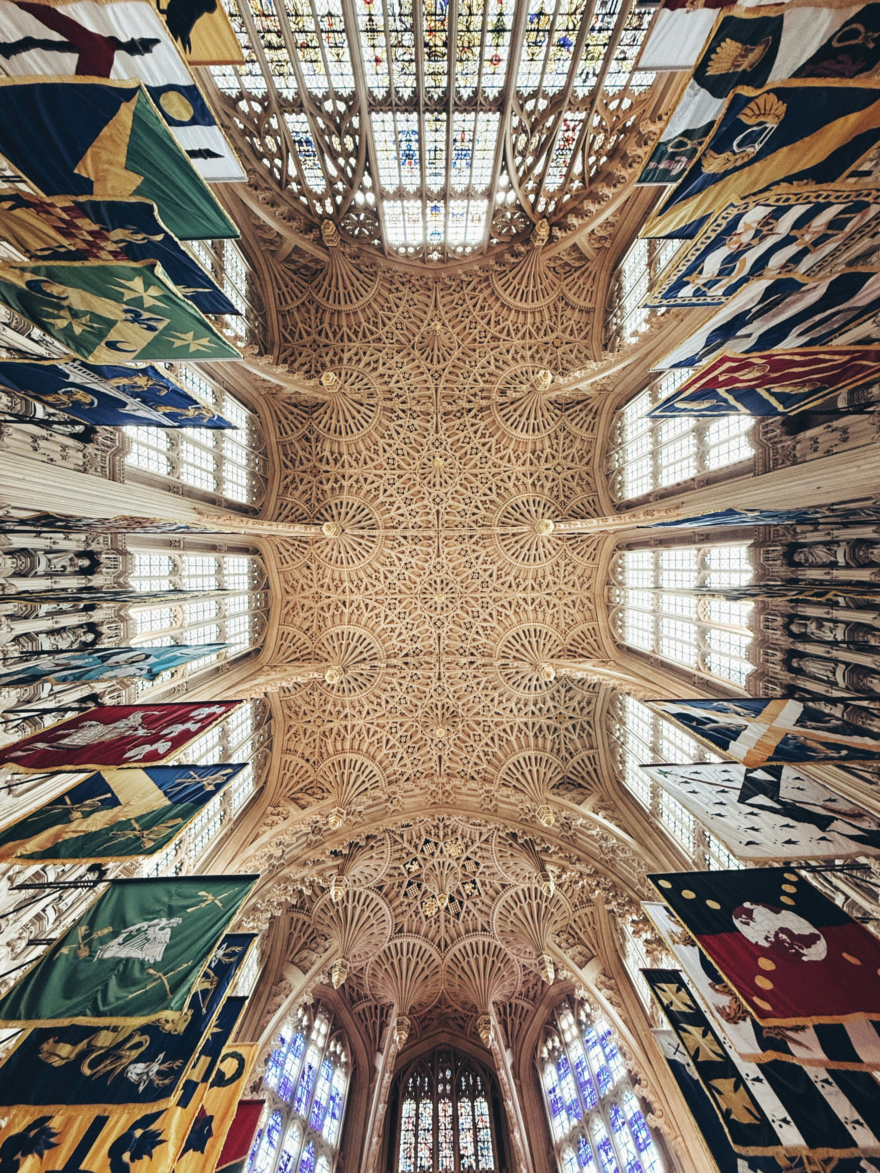 Intricate vaulted ceiling adorned with colorful flags in a grand hall, showcasing historical significance and architectural beauty.
