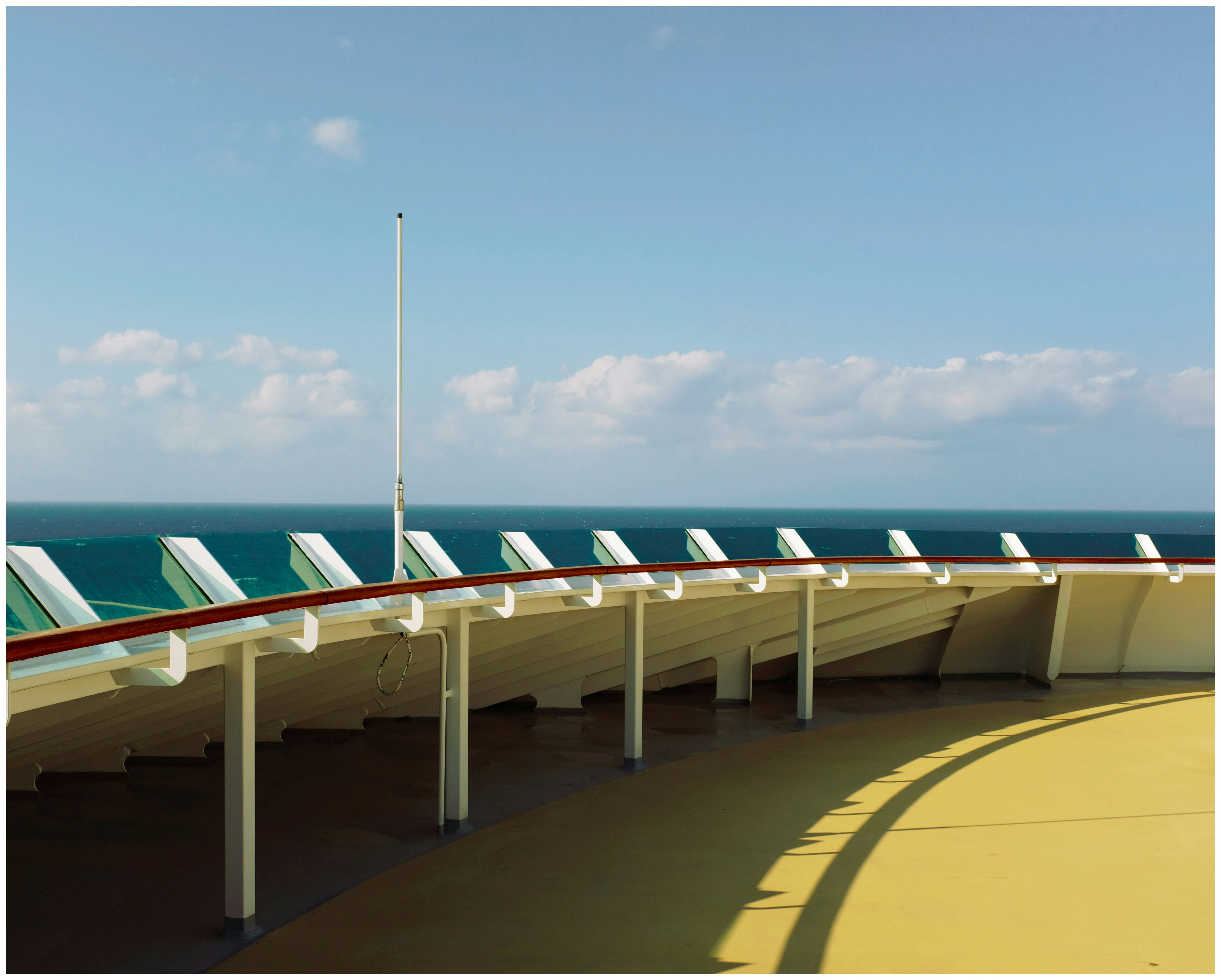 Deck railing overlooking the blue ocean under sky