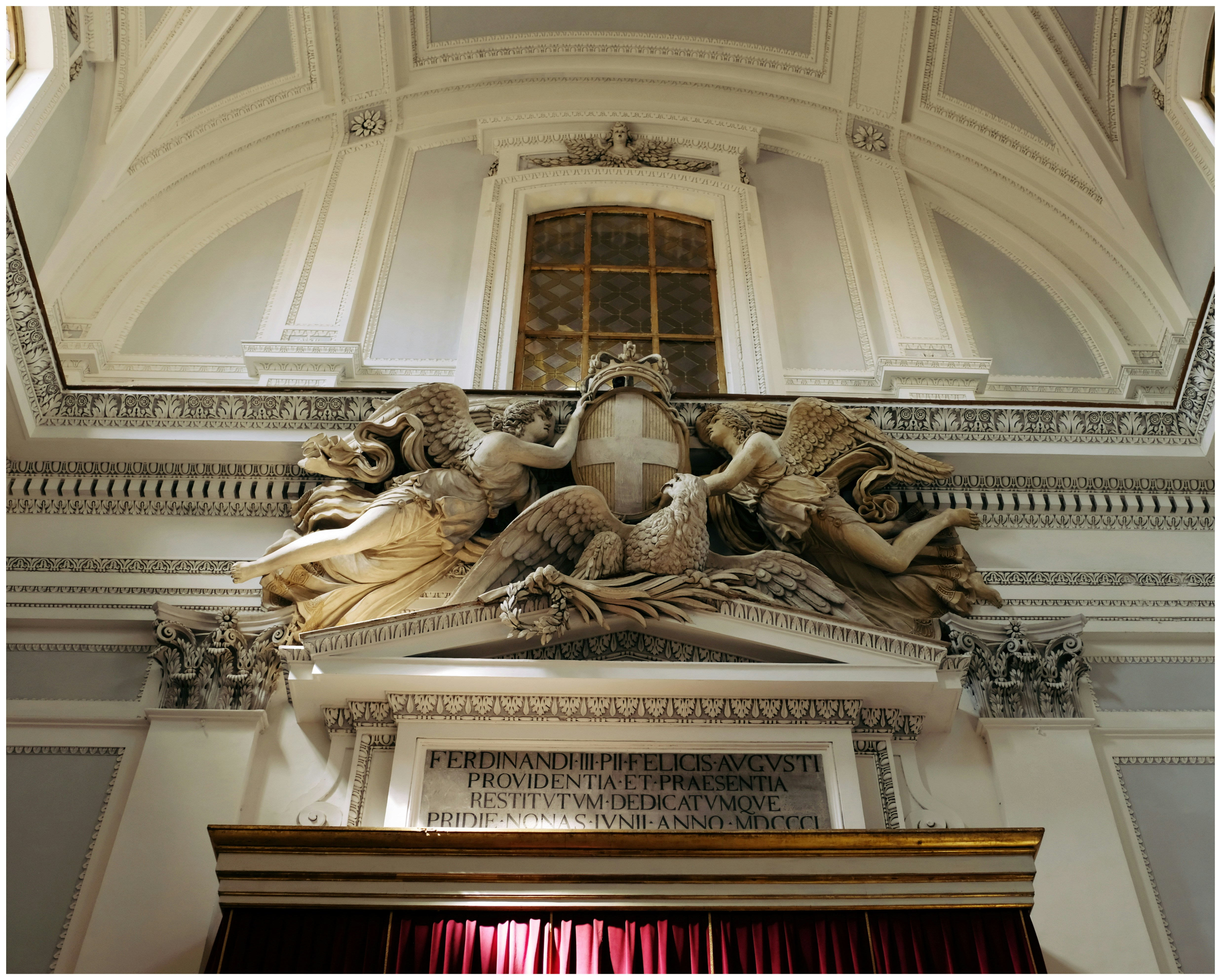 Winged Guardians Framing a Latin Crest Above Velvet Proscenium