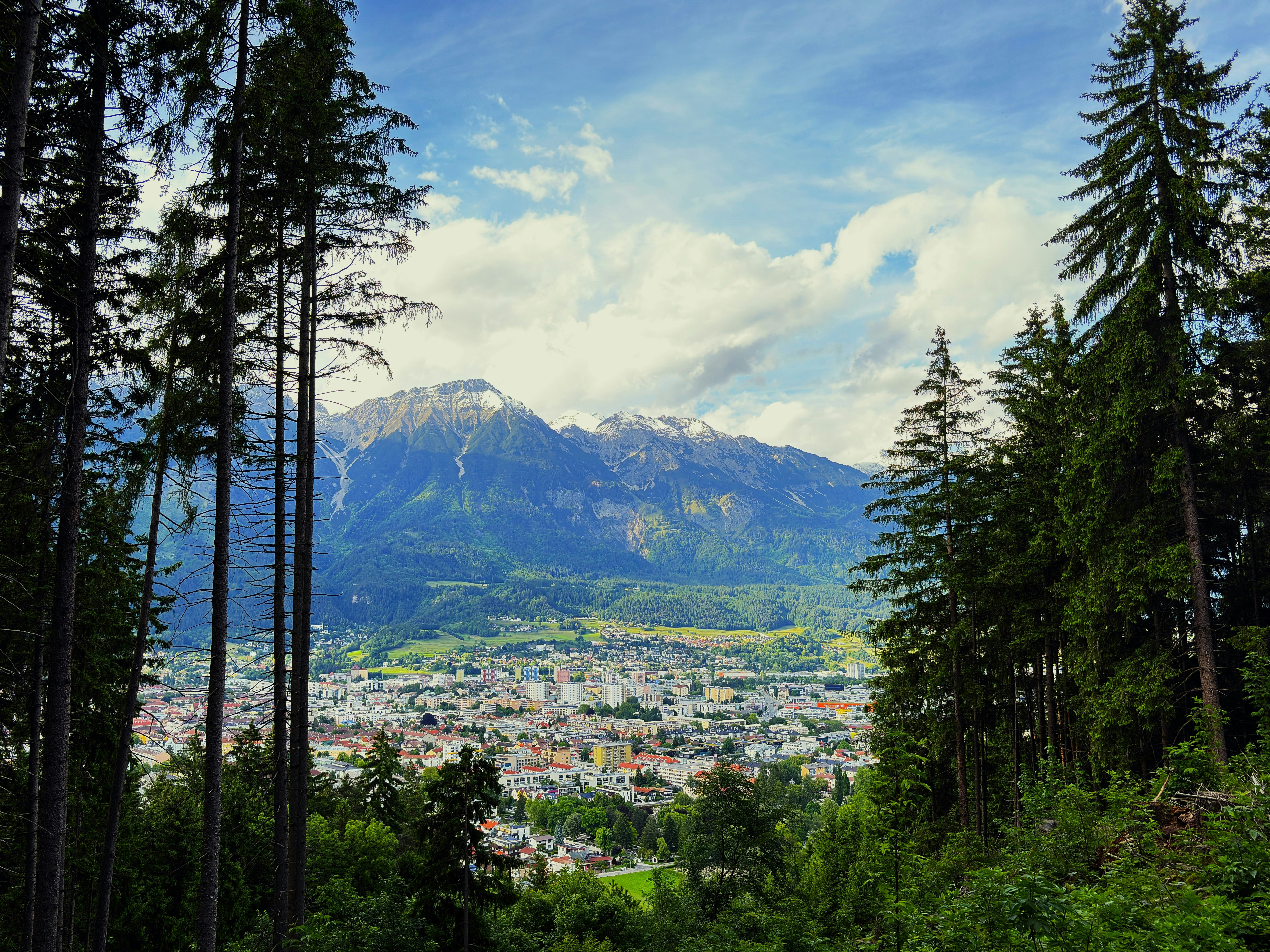 Innsbruck, Austria | Forest frames view of town and snow-capped mountains.