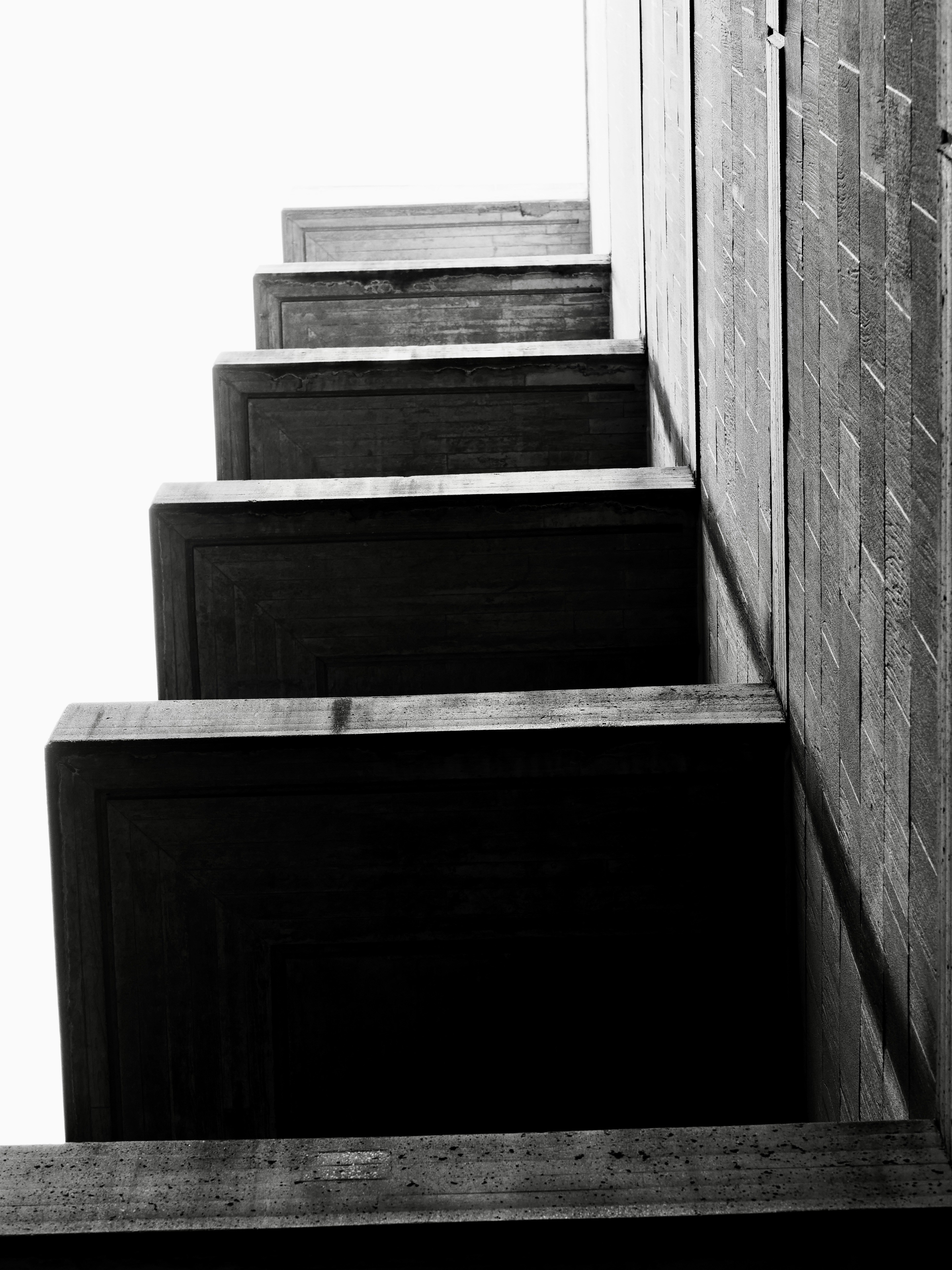 Facade of a modern building | A dark staircase leading upwards against a bright white wall.