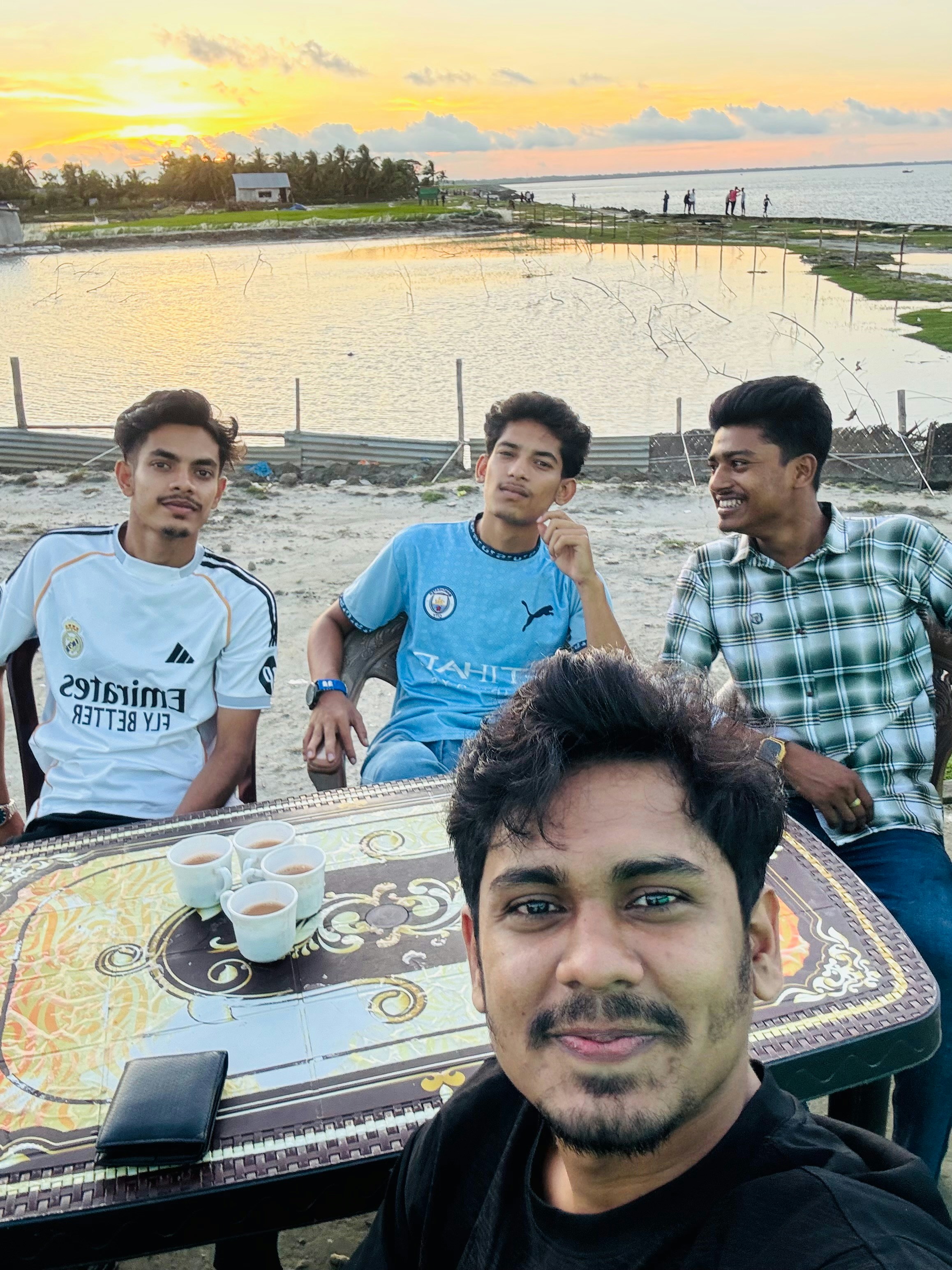 Shovon Ahmed at Noakhali, Bangladesh | Four young men enjoy tea by the ocean at sunset.