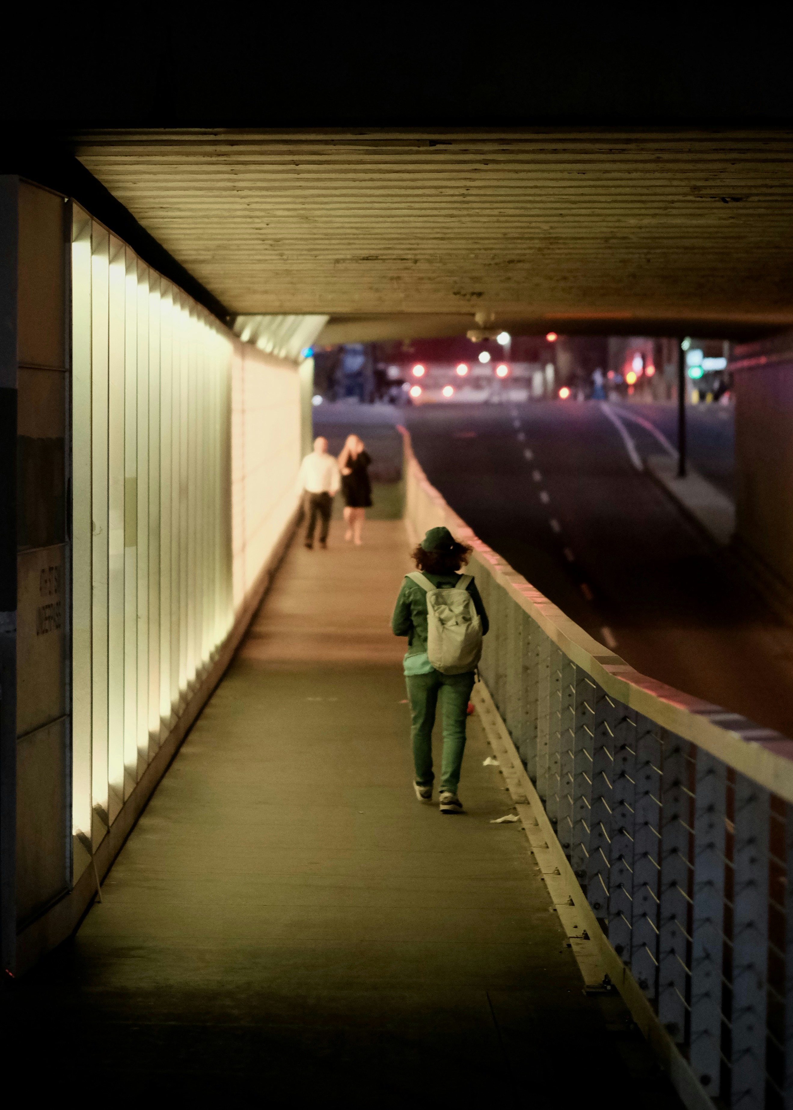Person walking on illuminated pedestrian walkway at night