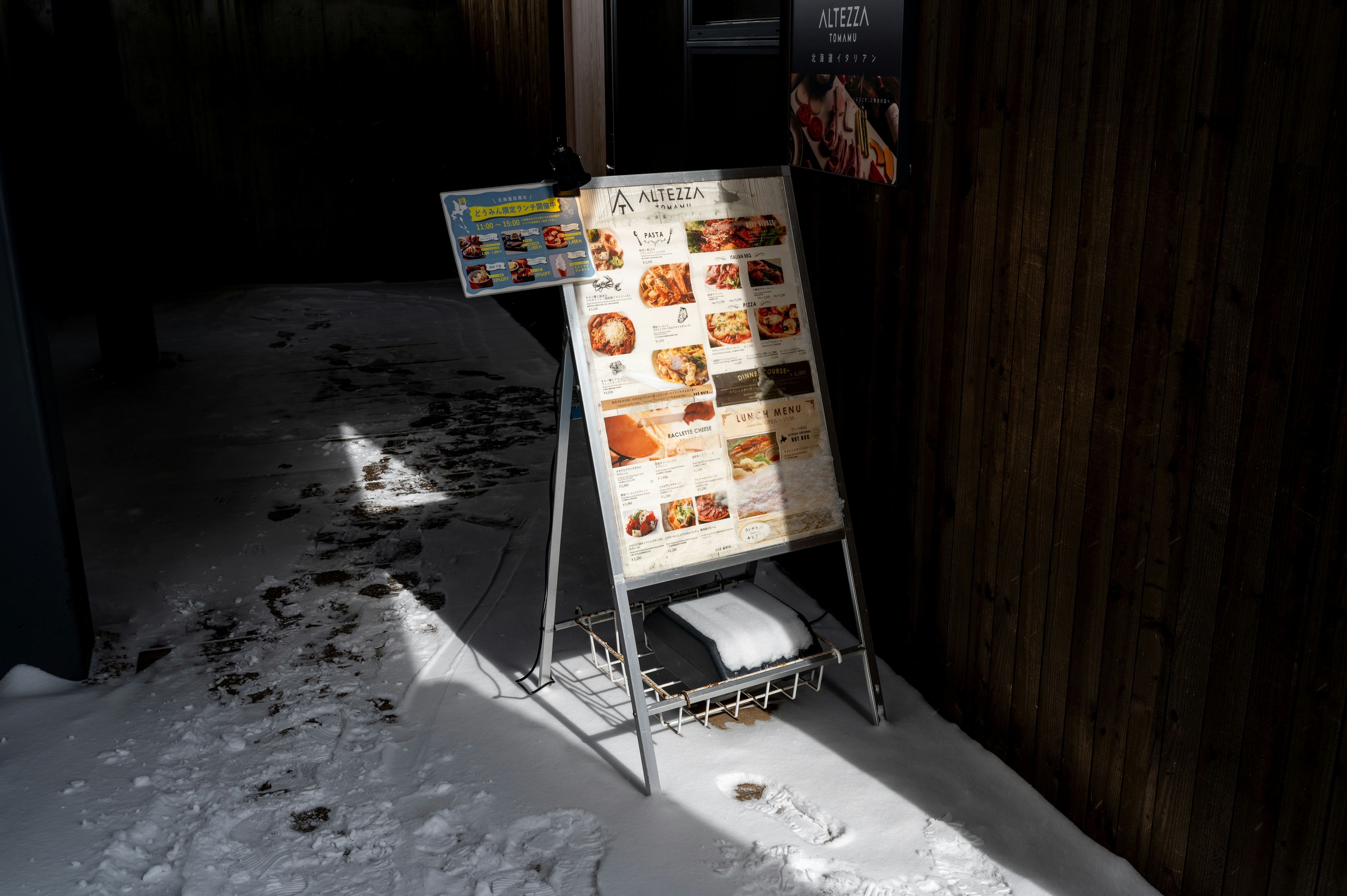A menu board stands in the snow outside.