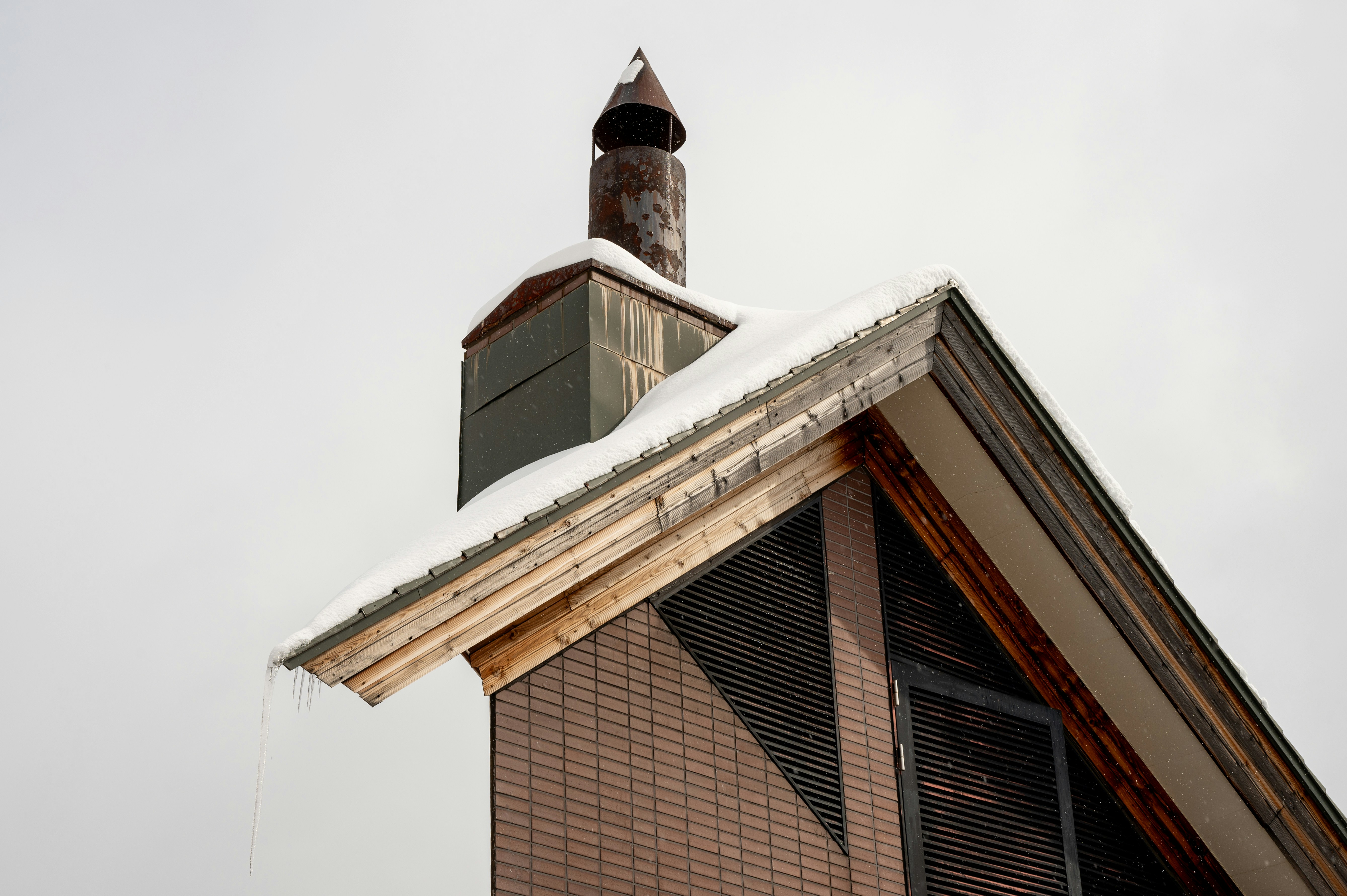 Snow-covered rooftop with a brick chimney.