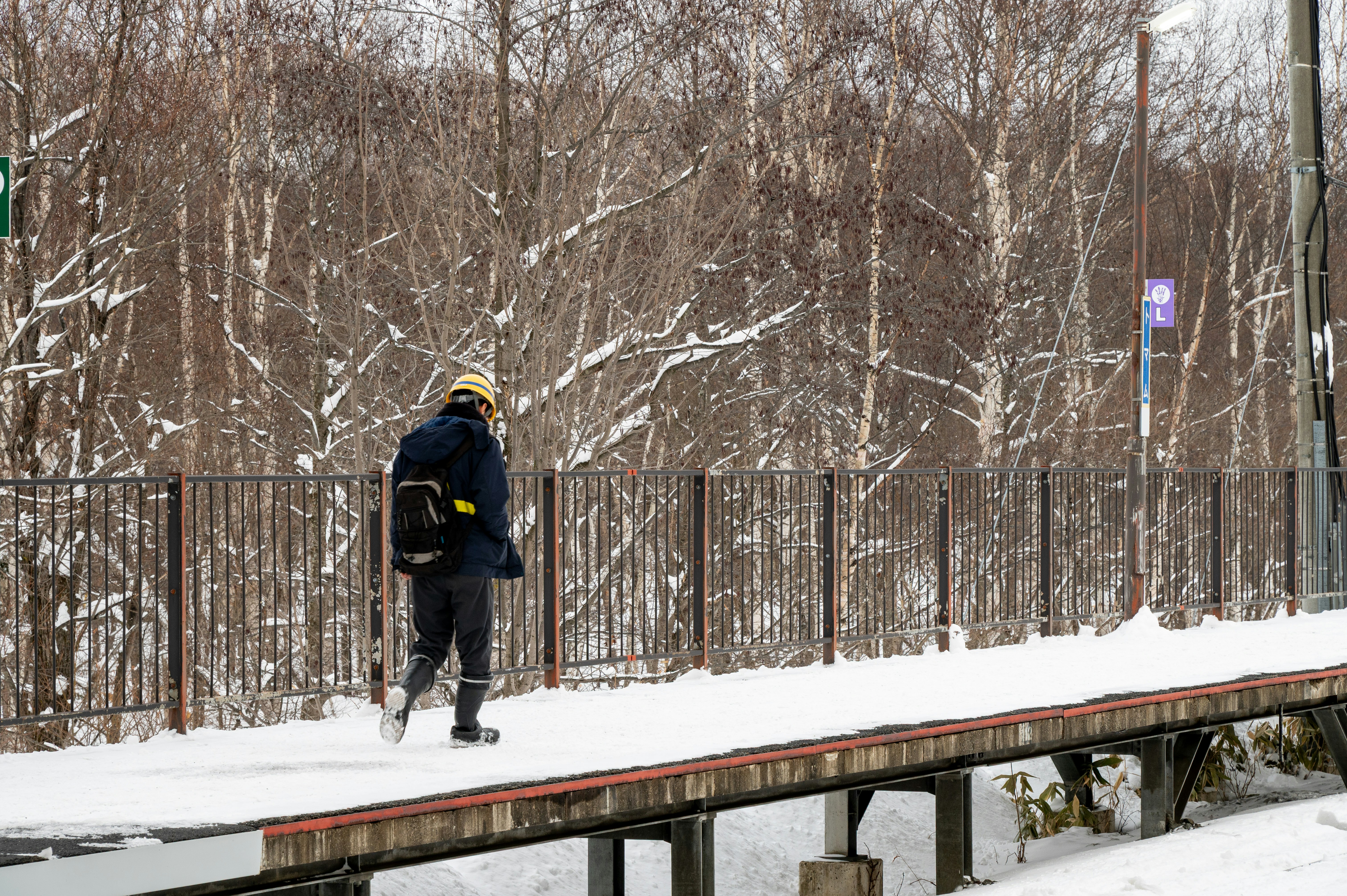 Person walking on a snowy train platform.