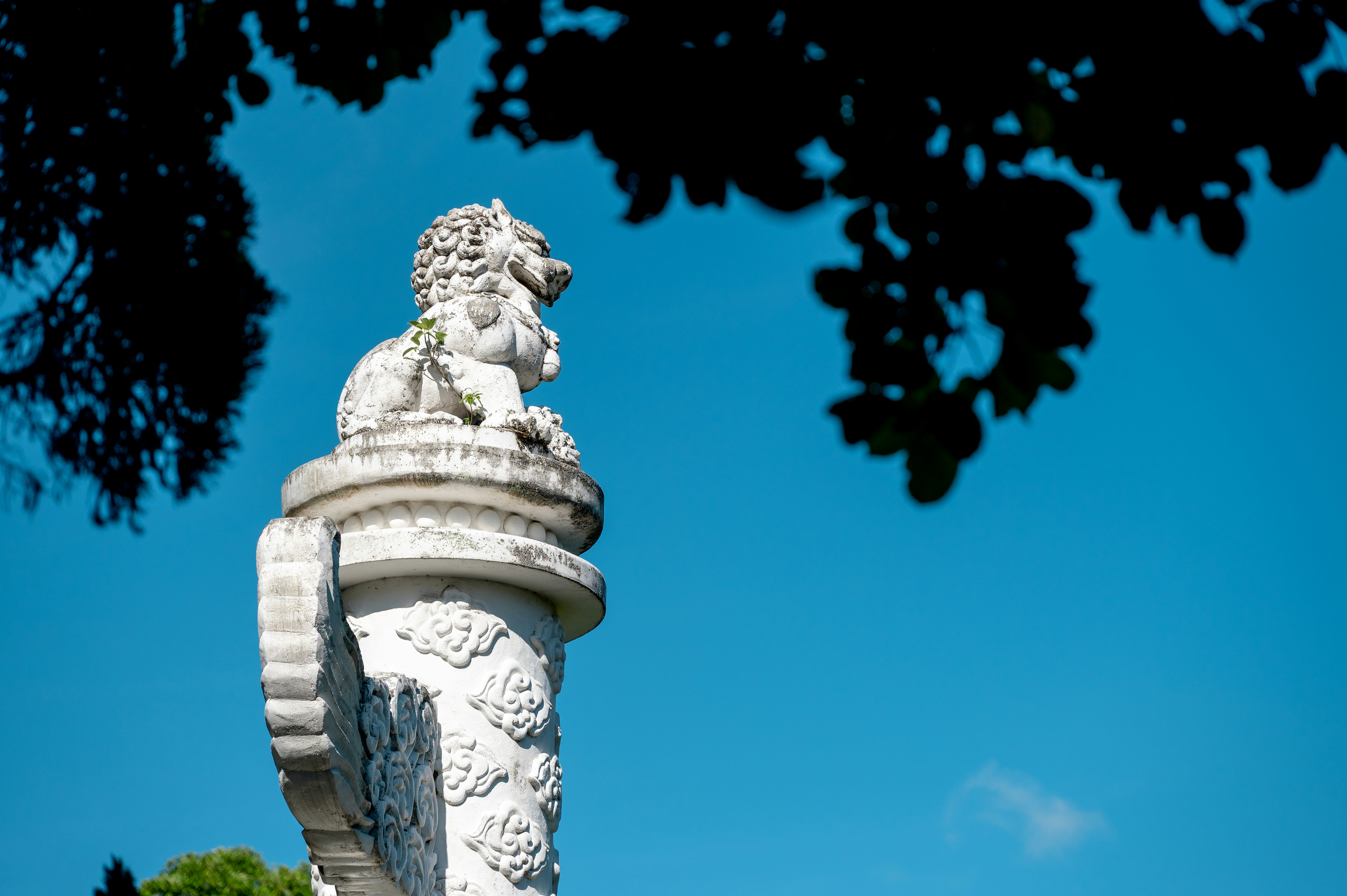Stone lion statue on a pedestal against blue sky