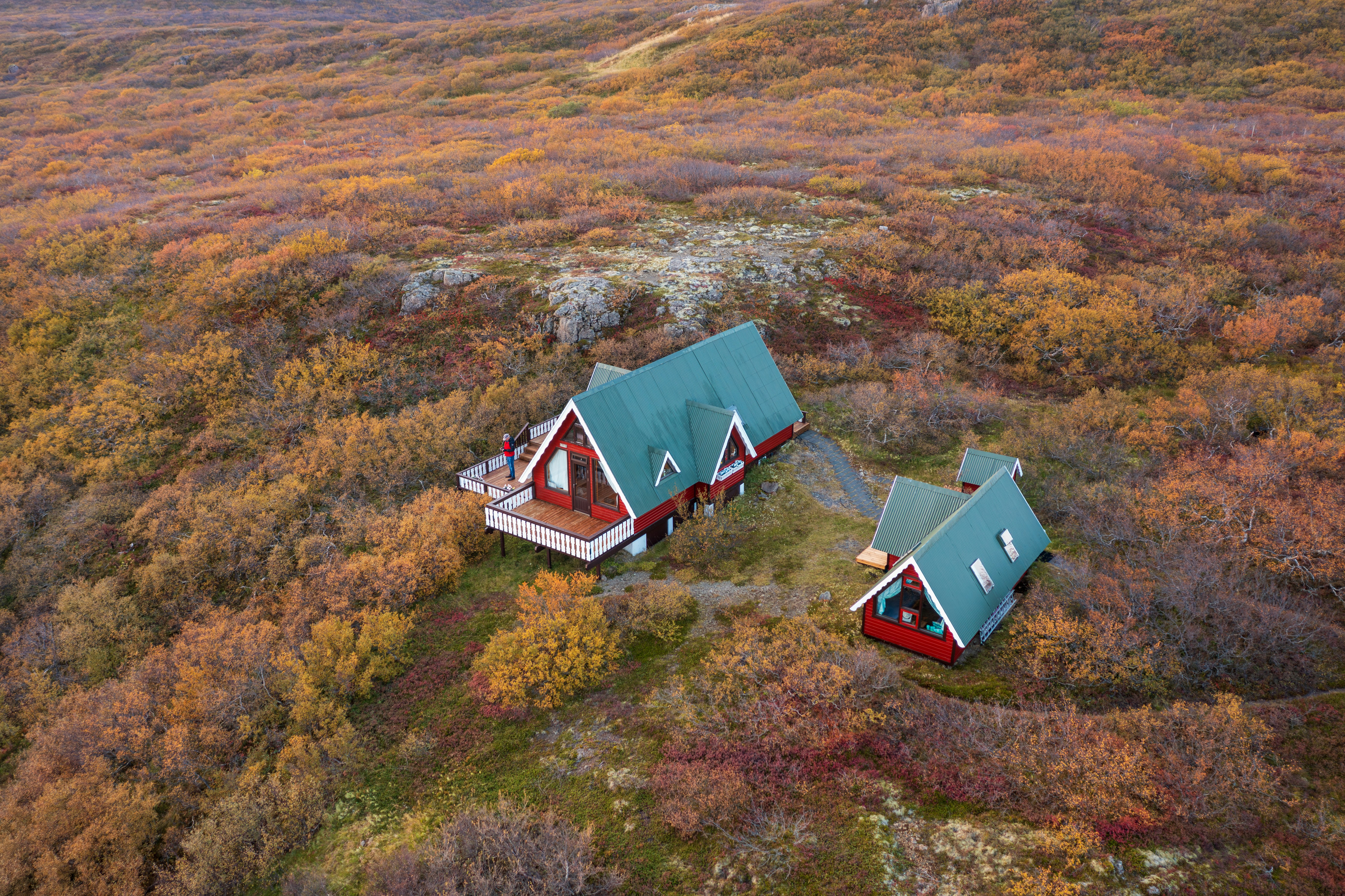 Two cabins nestled in autumn foliage from above.
