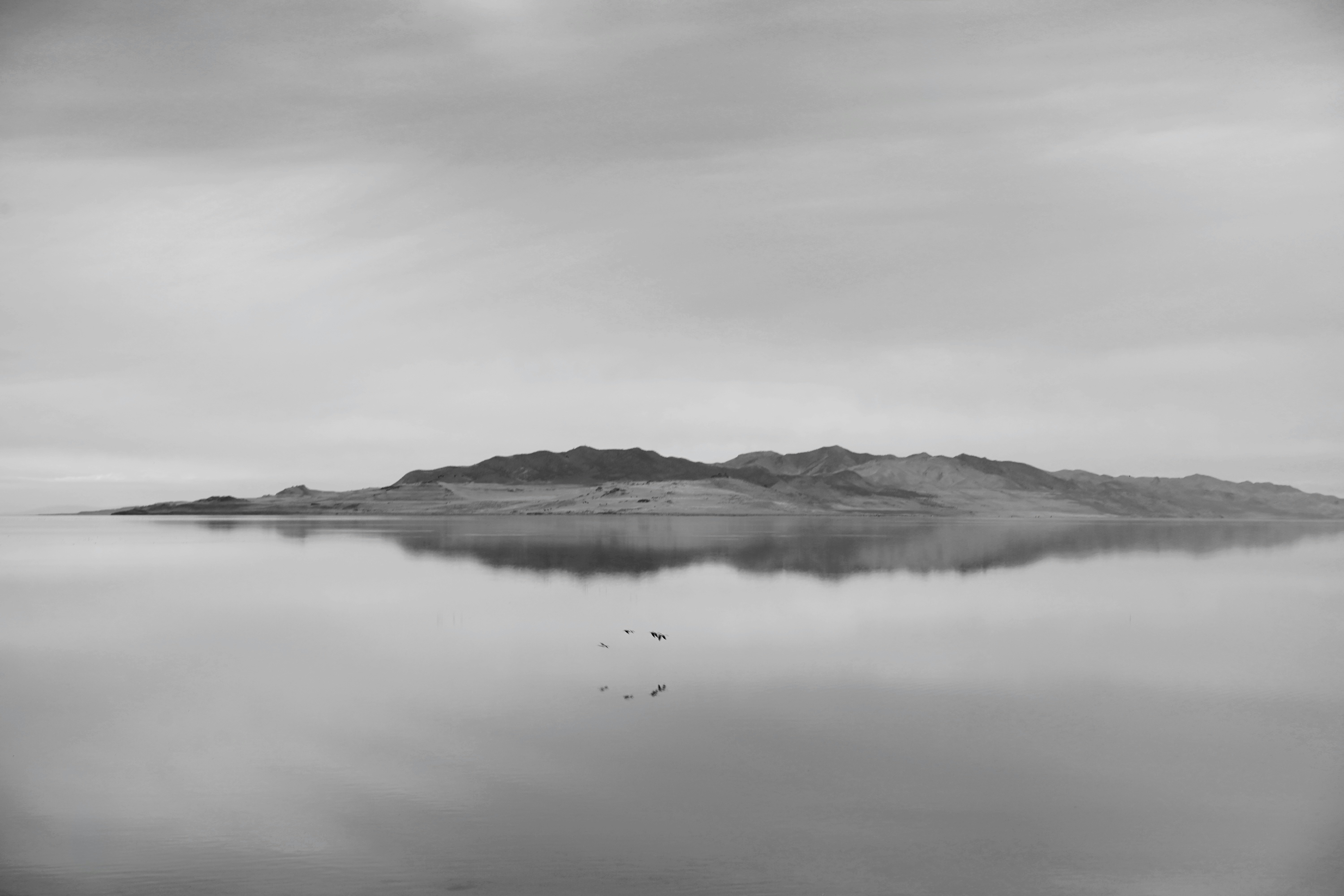 Island reflected on calm water under cloudy sky
