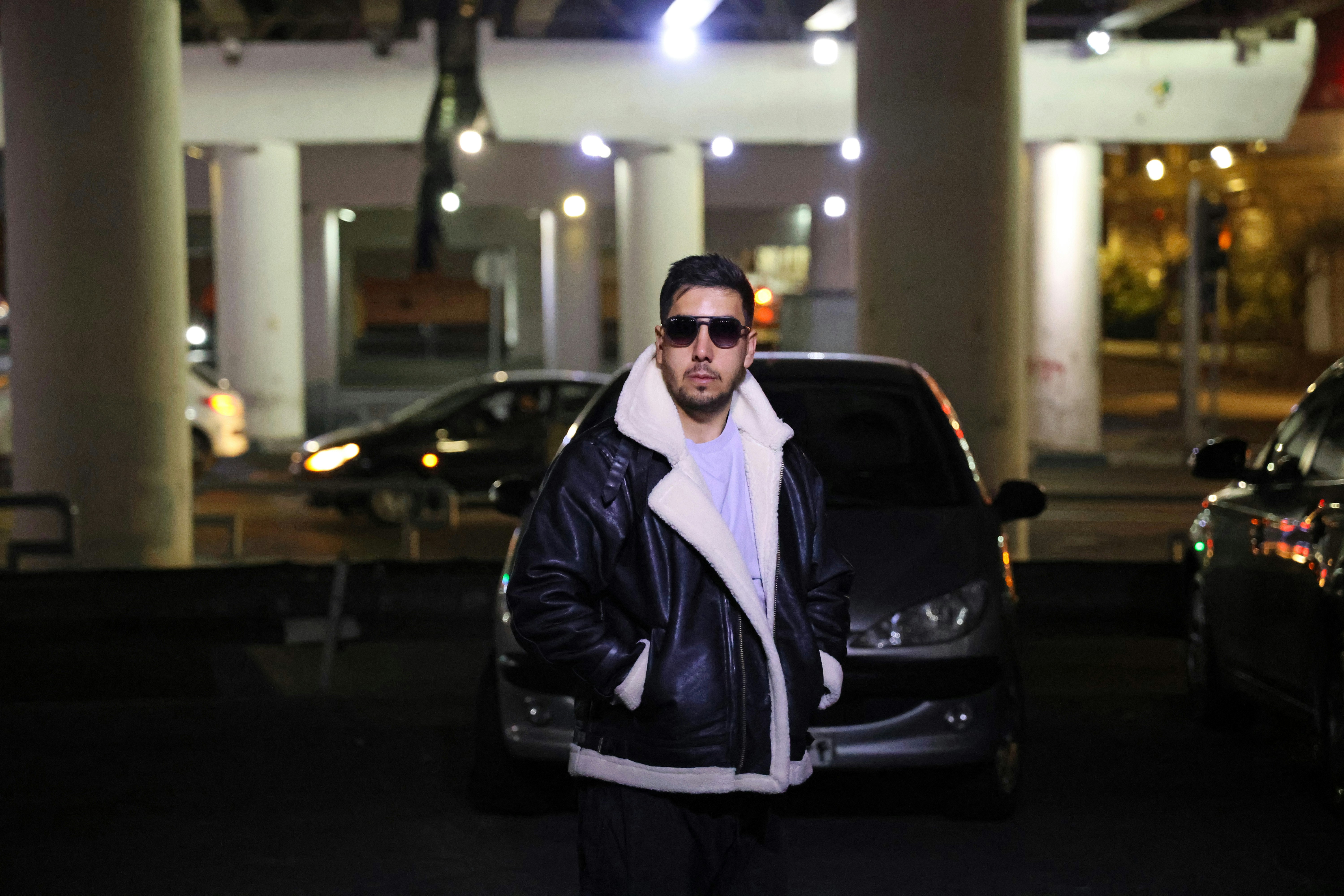 Man in a leather jacket standing in front of car