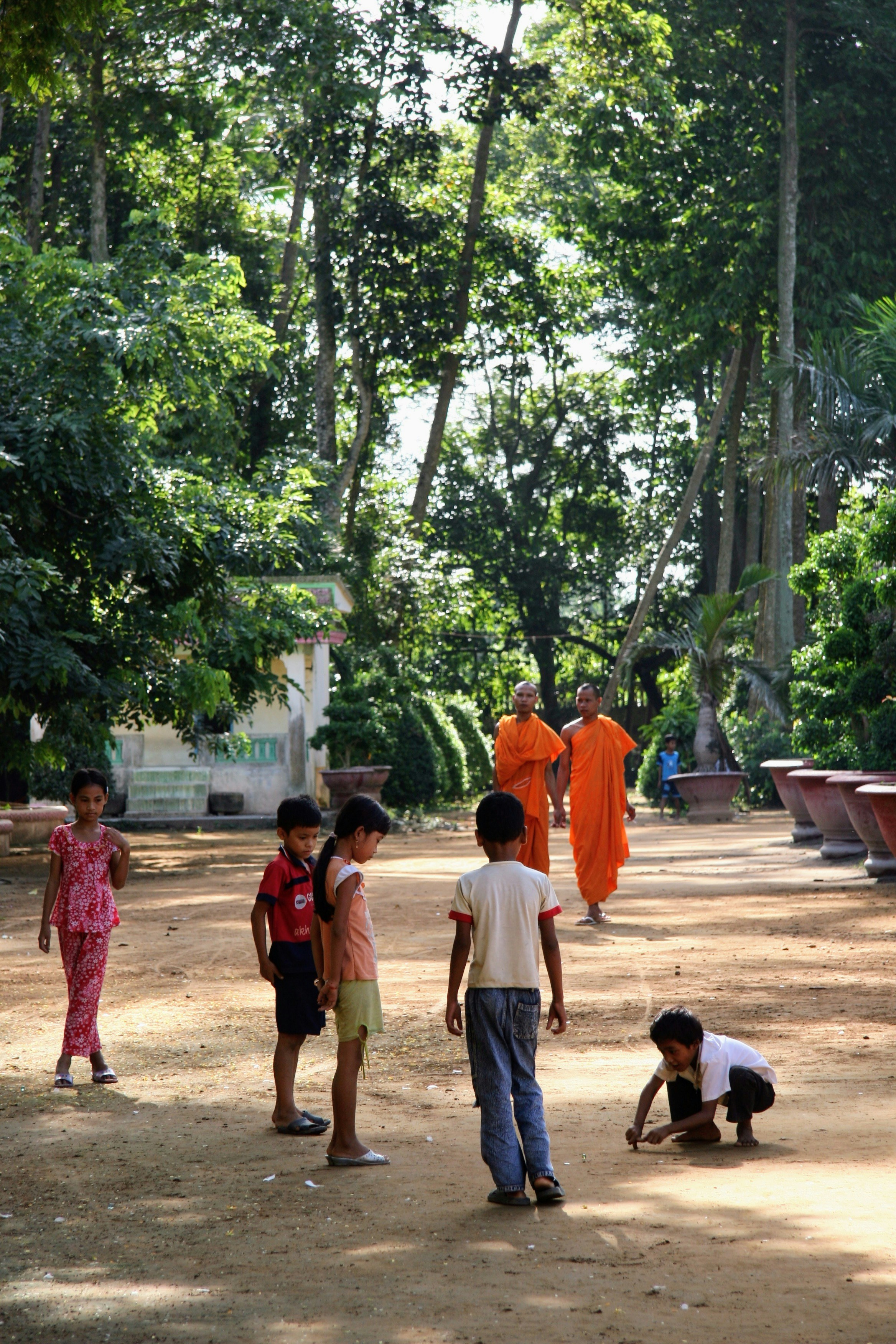 Children play in a courtyard with monks in the background.