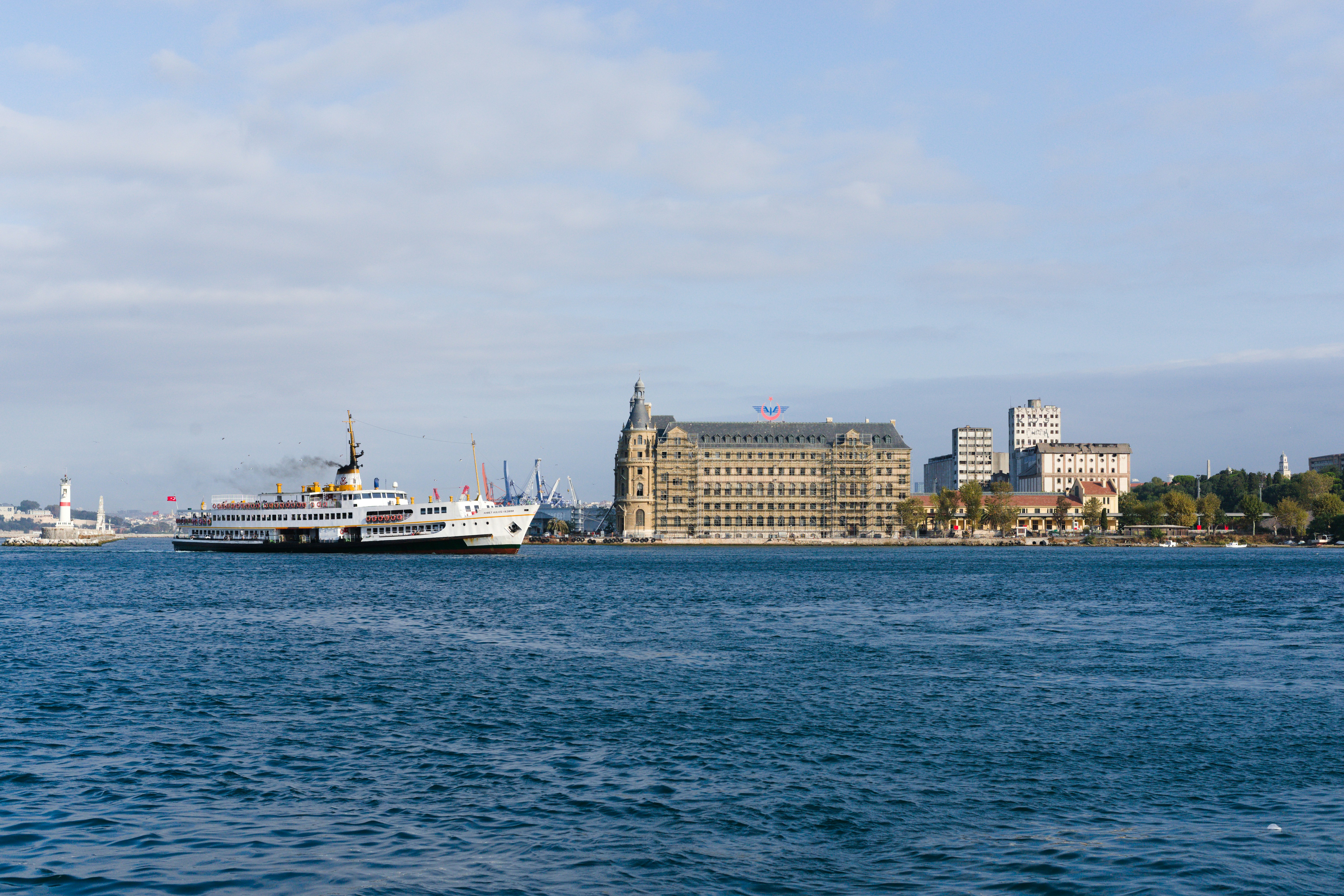 Ferry boat sails past historic building by the water.