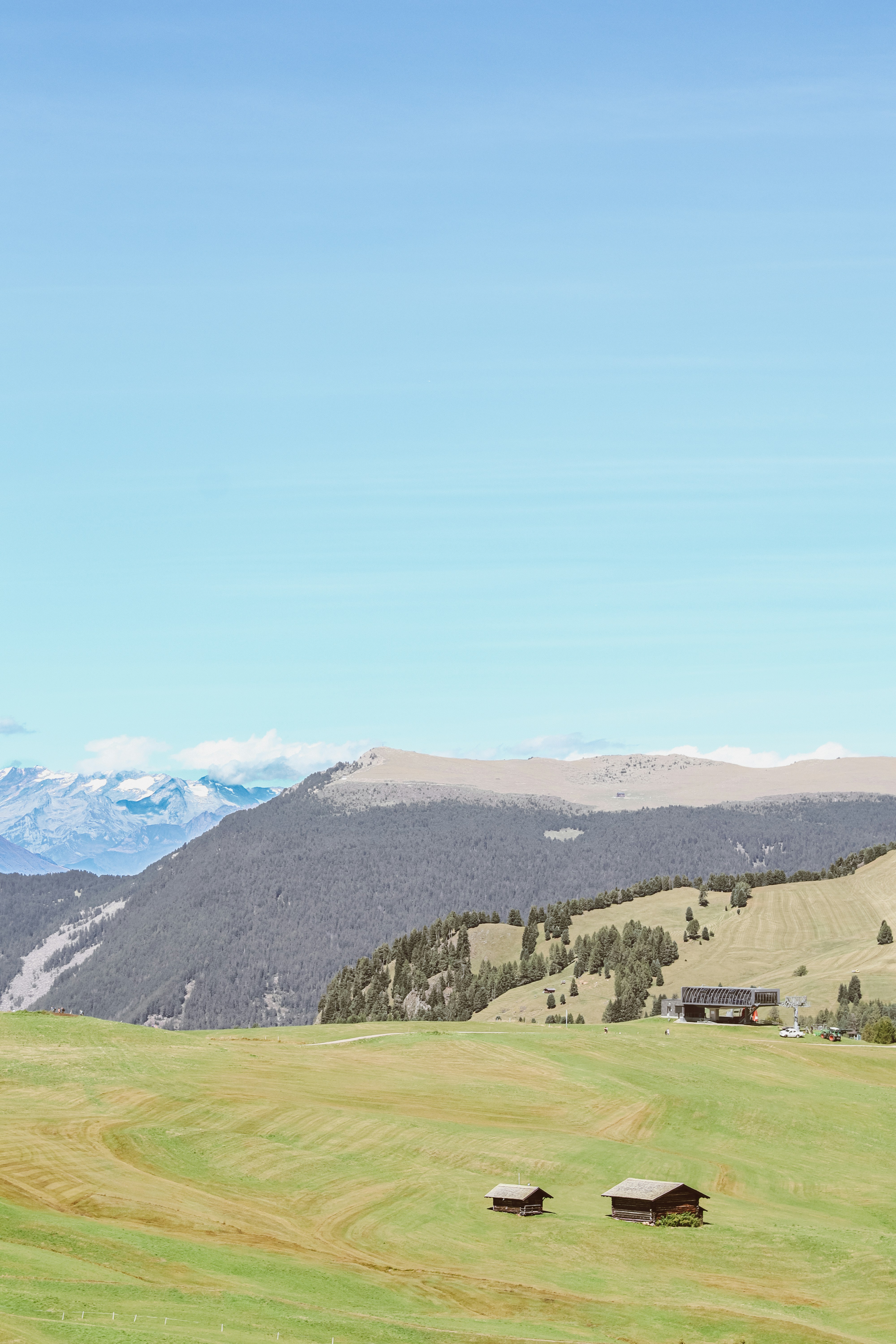 Two small wooden cabins in a green mountain meadow.