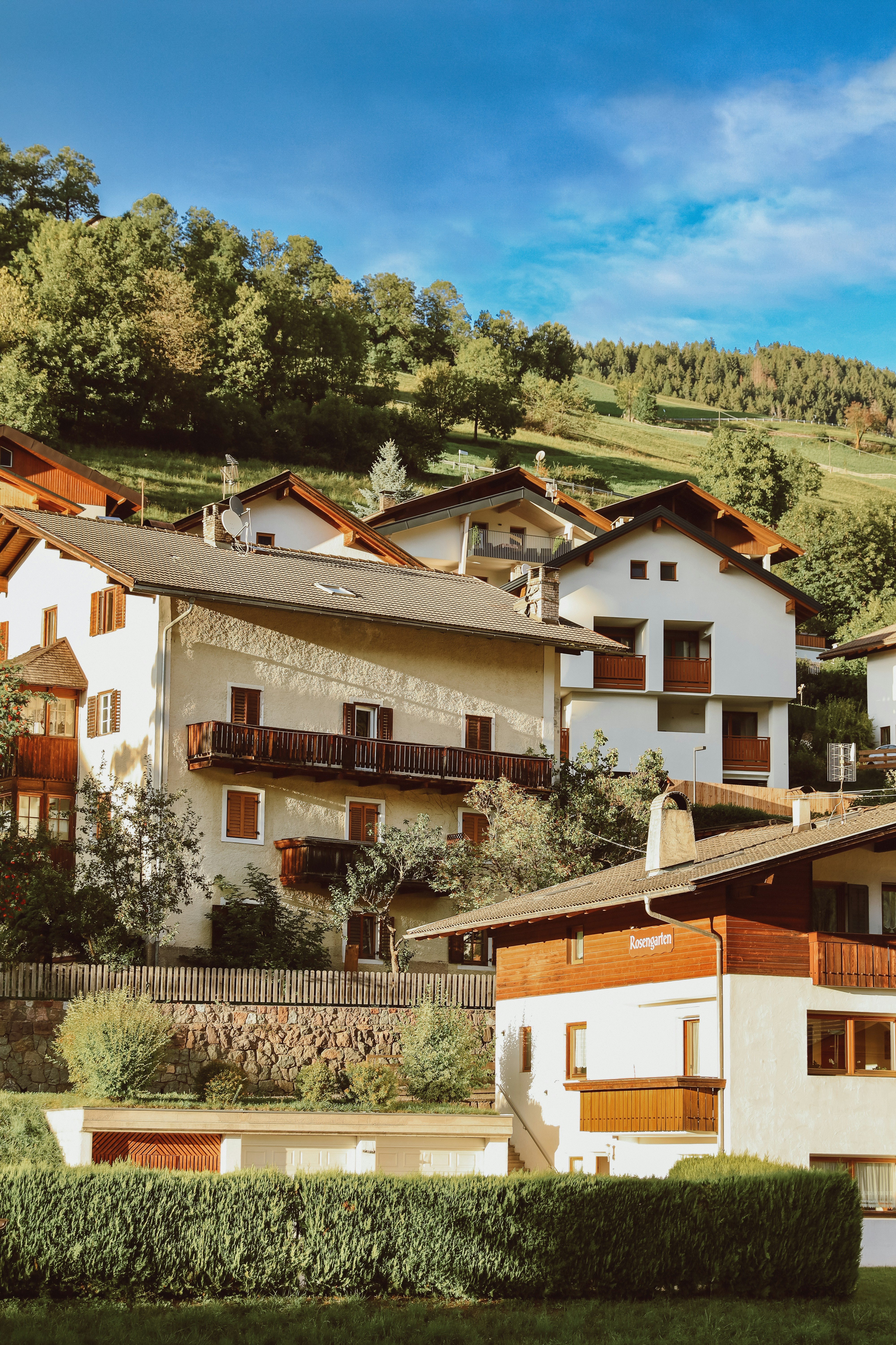 White houses nestled on a green hillside under blue sky.
