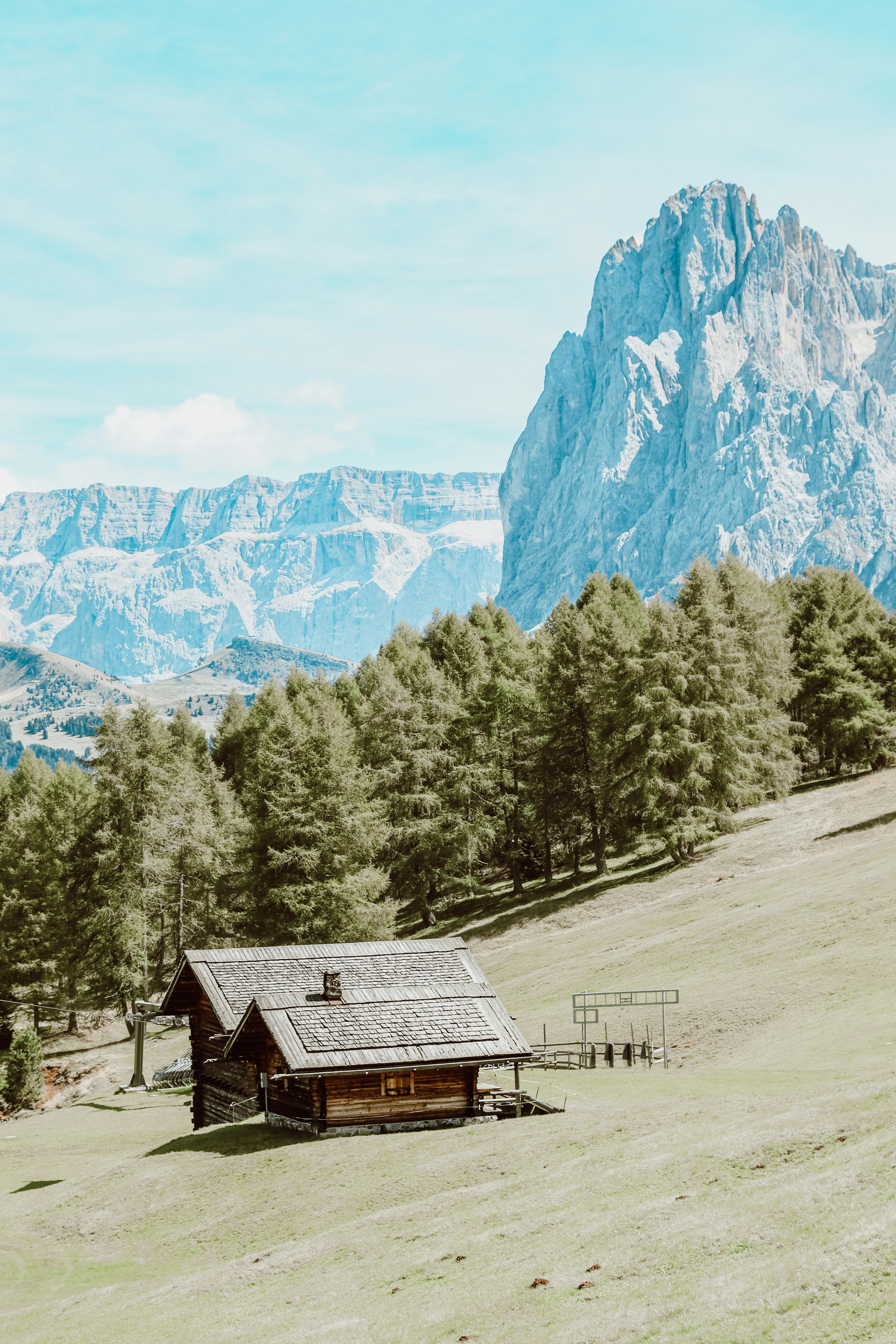Wooden cabin on a grassy hill with mountains behind