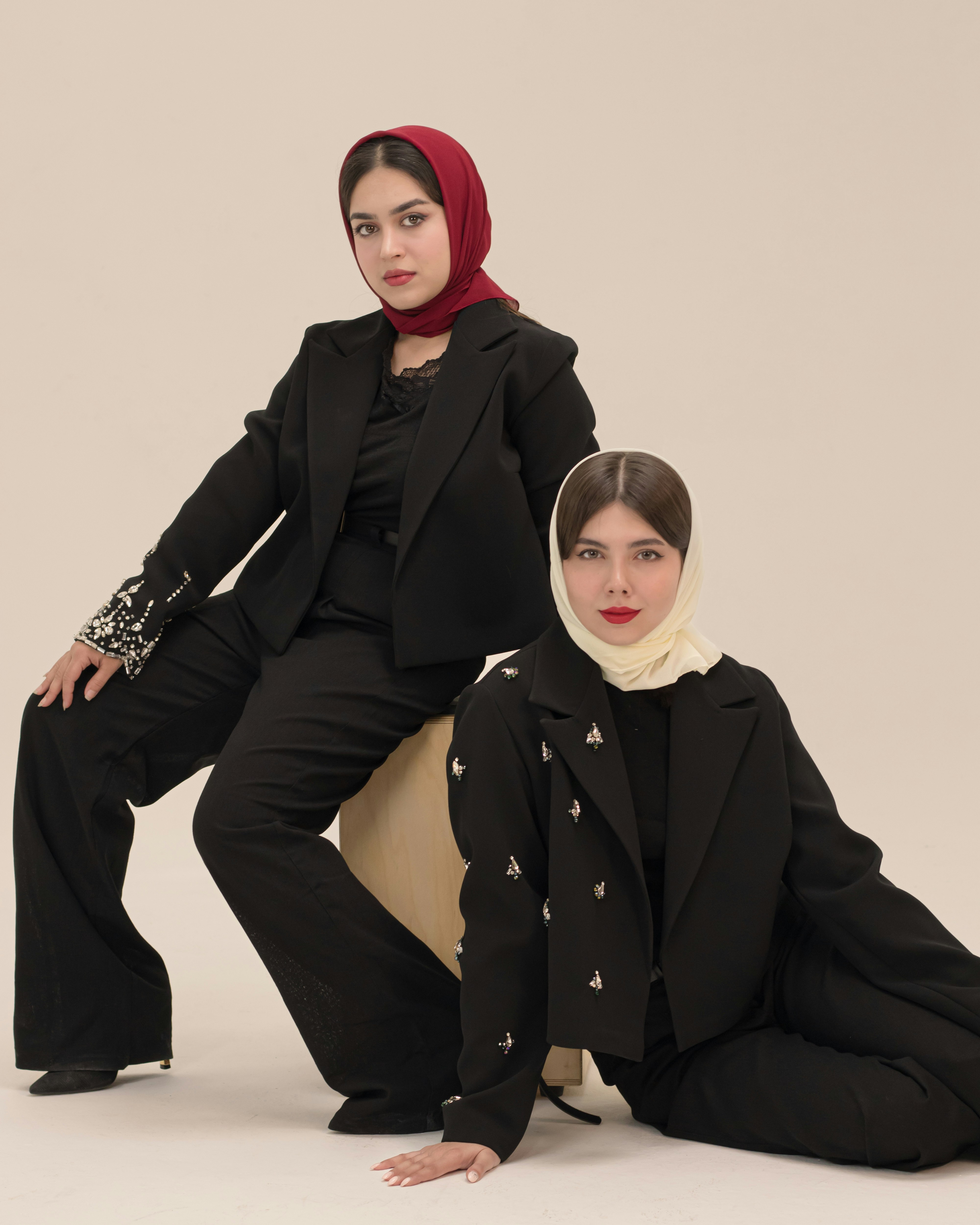 Two women in stylish black suits and hijabs.